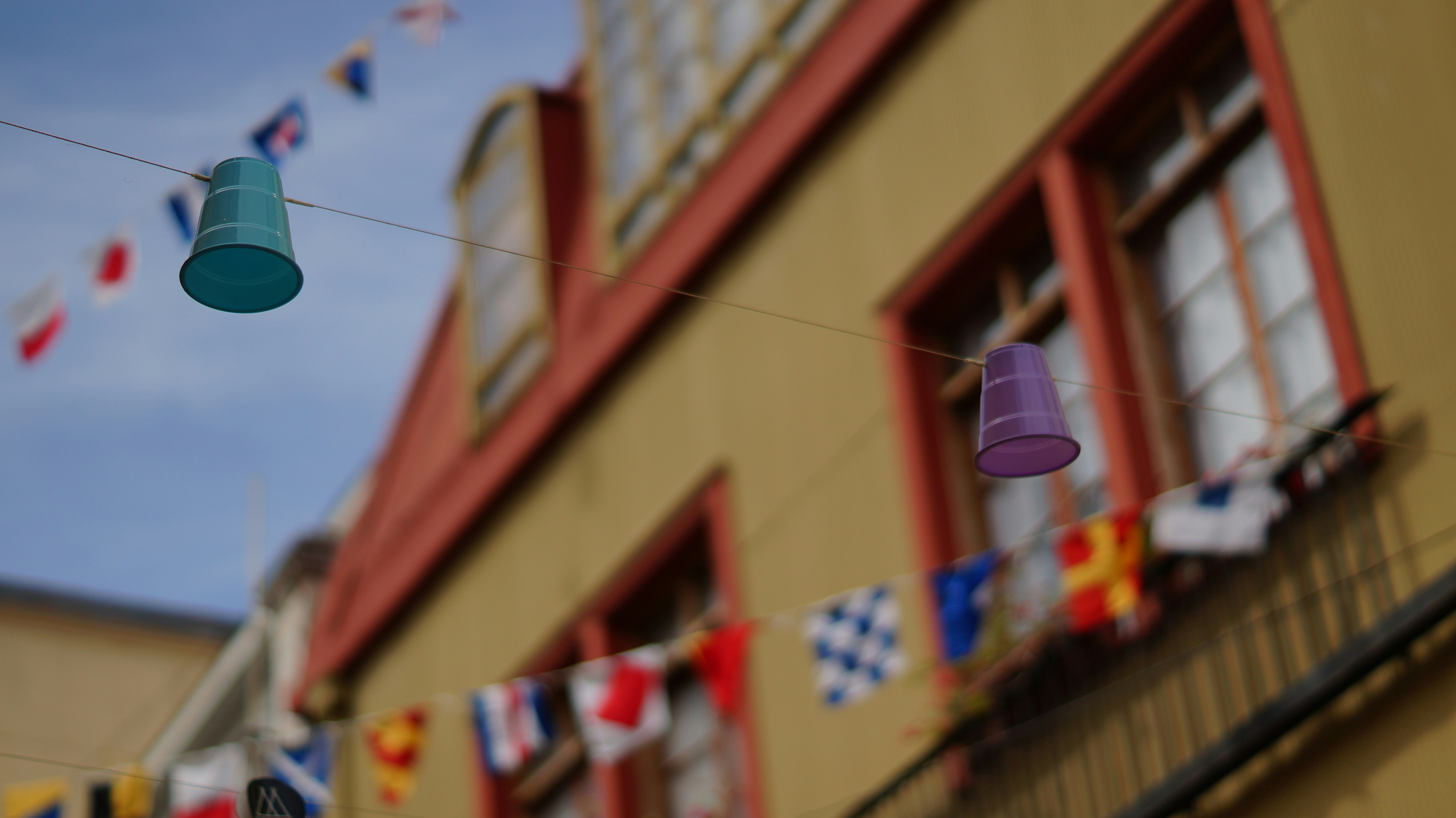 Colorful flags and paper lanterns strung between buildings against a blue sky.