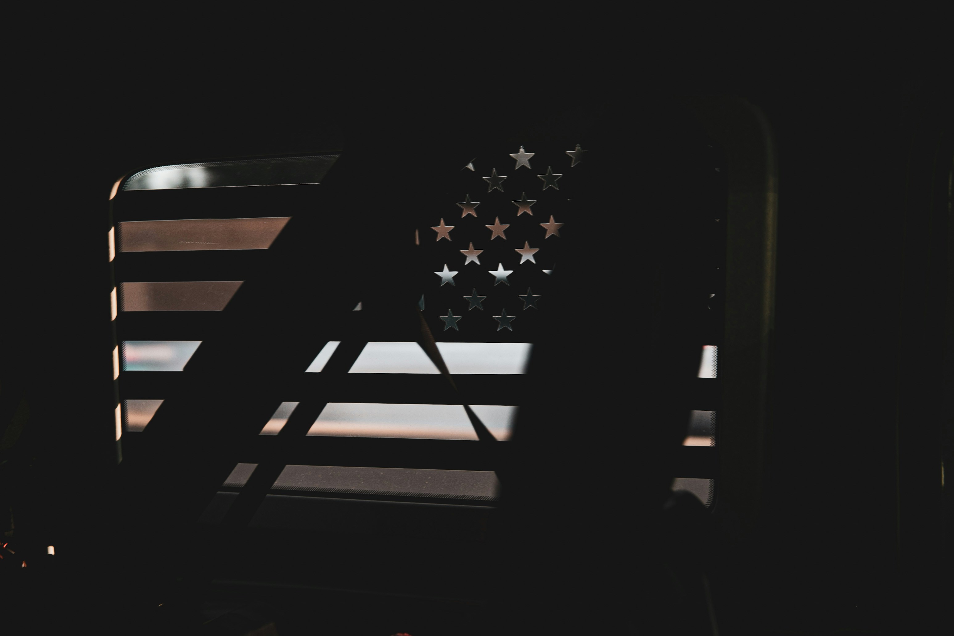 Stars Behind the Slats: A Flag Quietly Peering Through Shadowed Windows