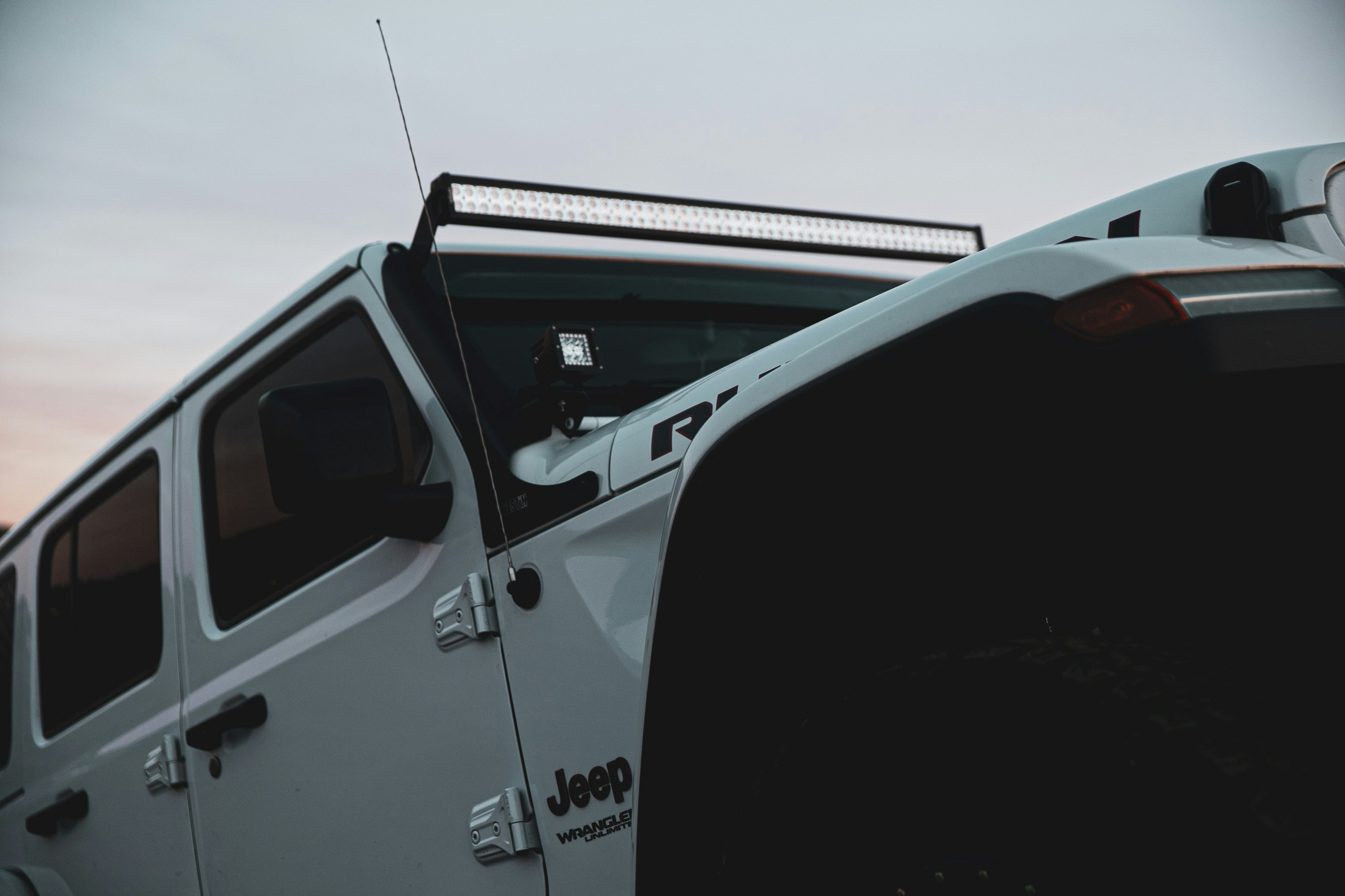 Edge of the Trail: White Jeep Wrangler under a roof-mounted LED light bar