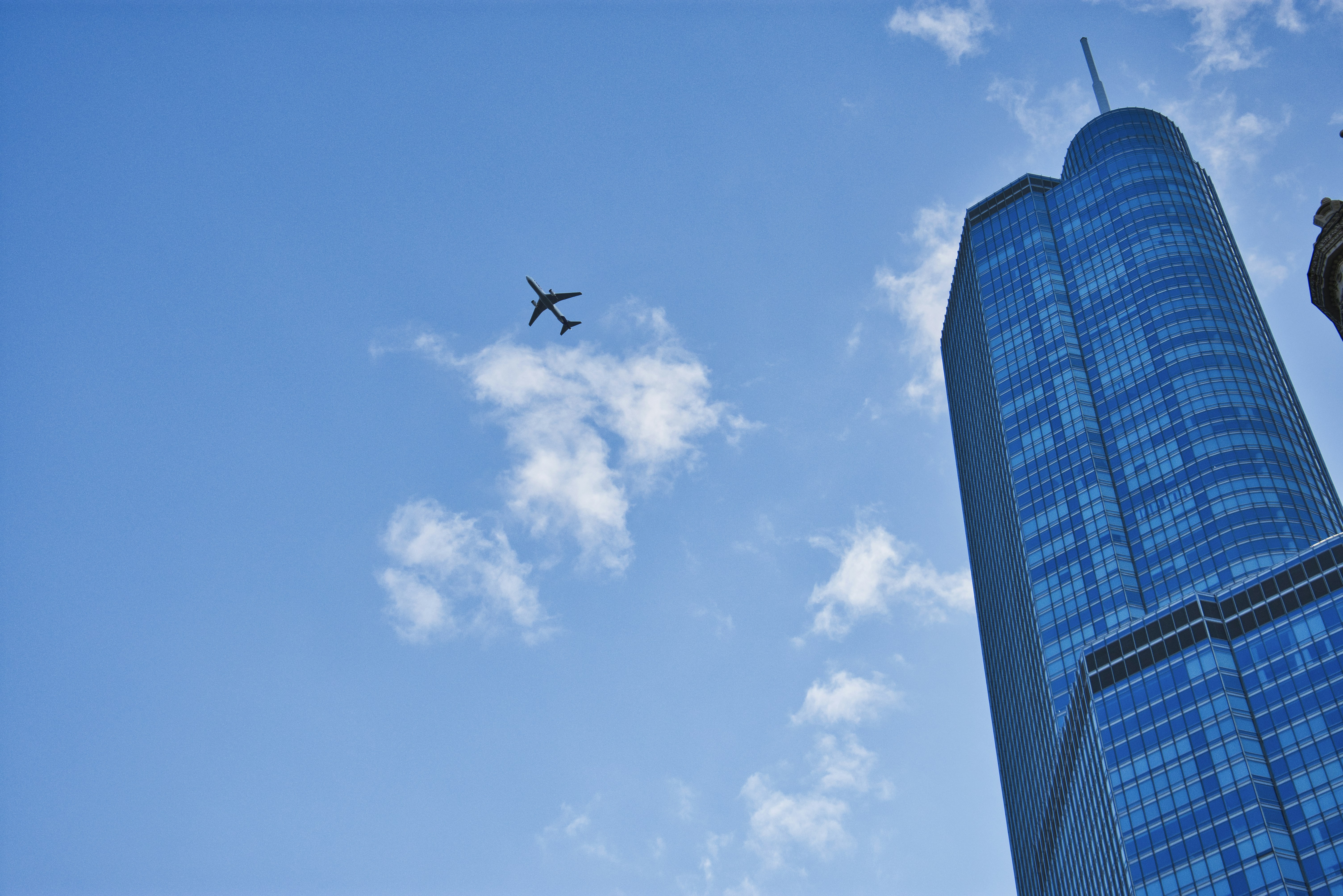 Jet Against Glass Skyline: A Lone Plane Over a Towering Glass Facade