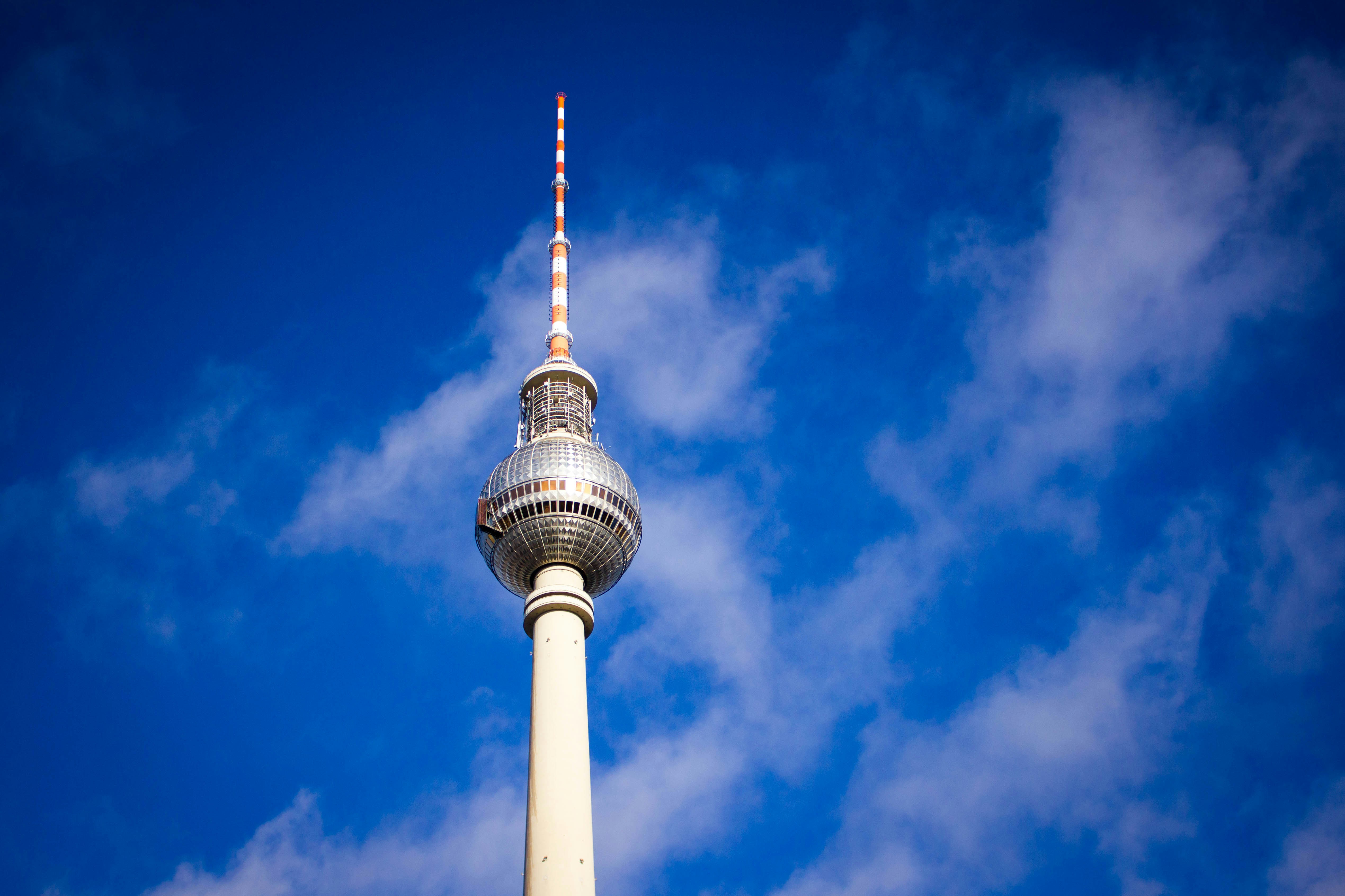 Berlin TV Tower rises majestically against a backdrop of vibrant blue sky, showcasing its distinctive design and structural elegance.