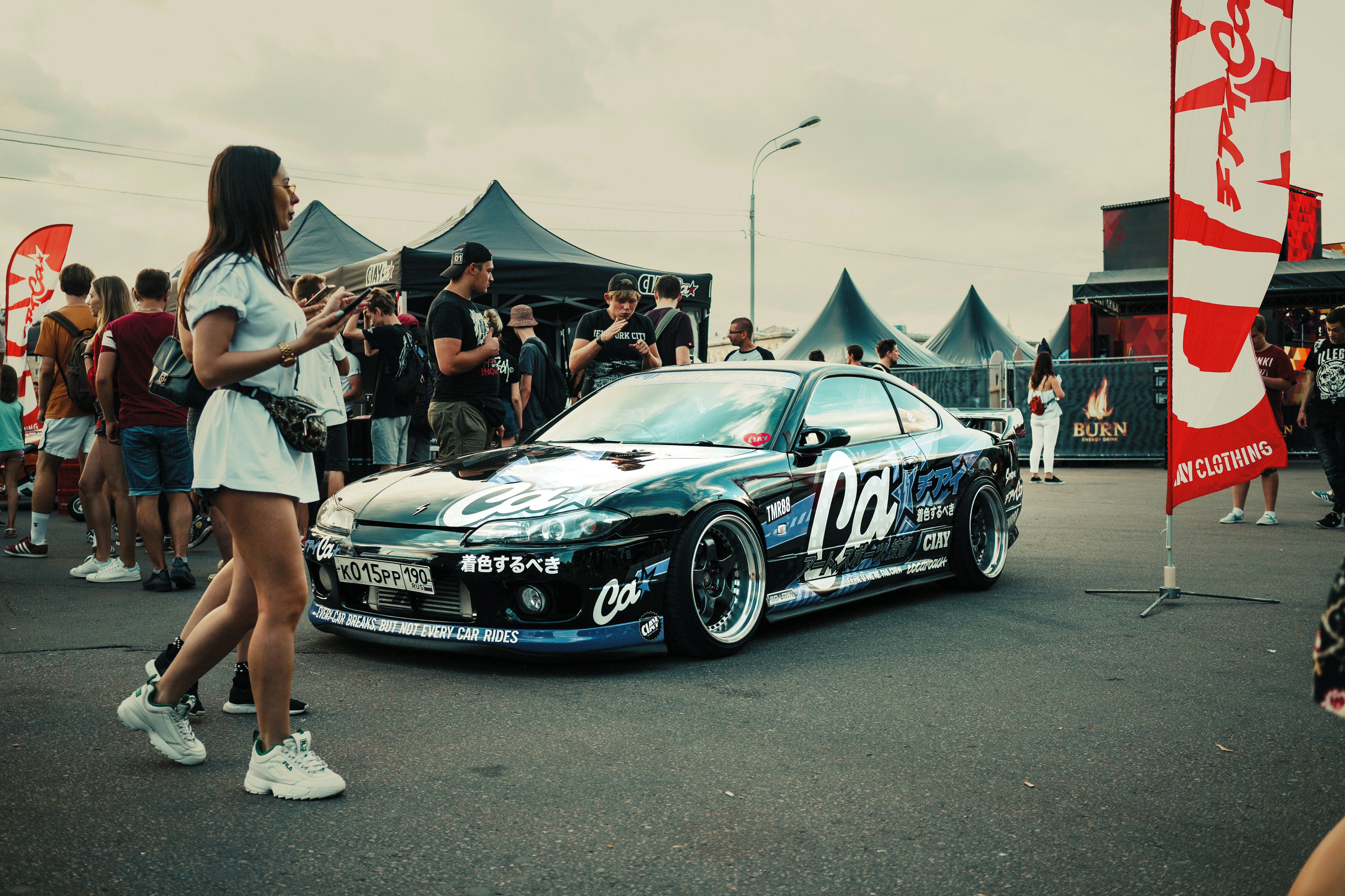 Low-slung race car on display amid a lively pit-scene at a car meet