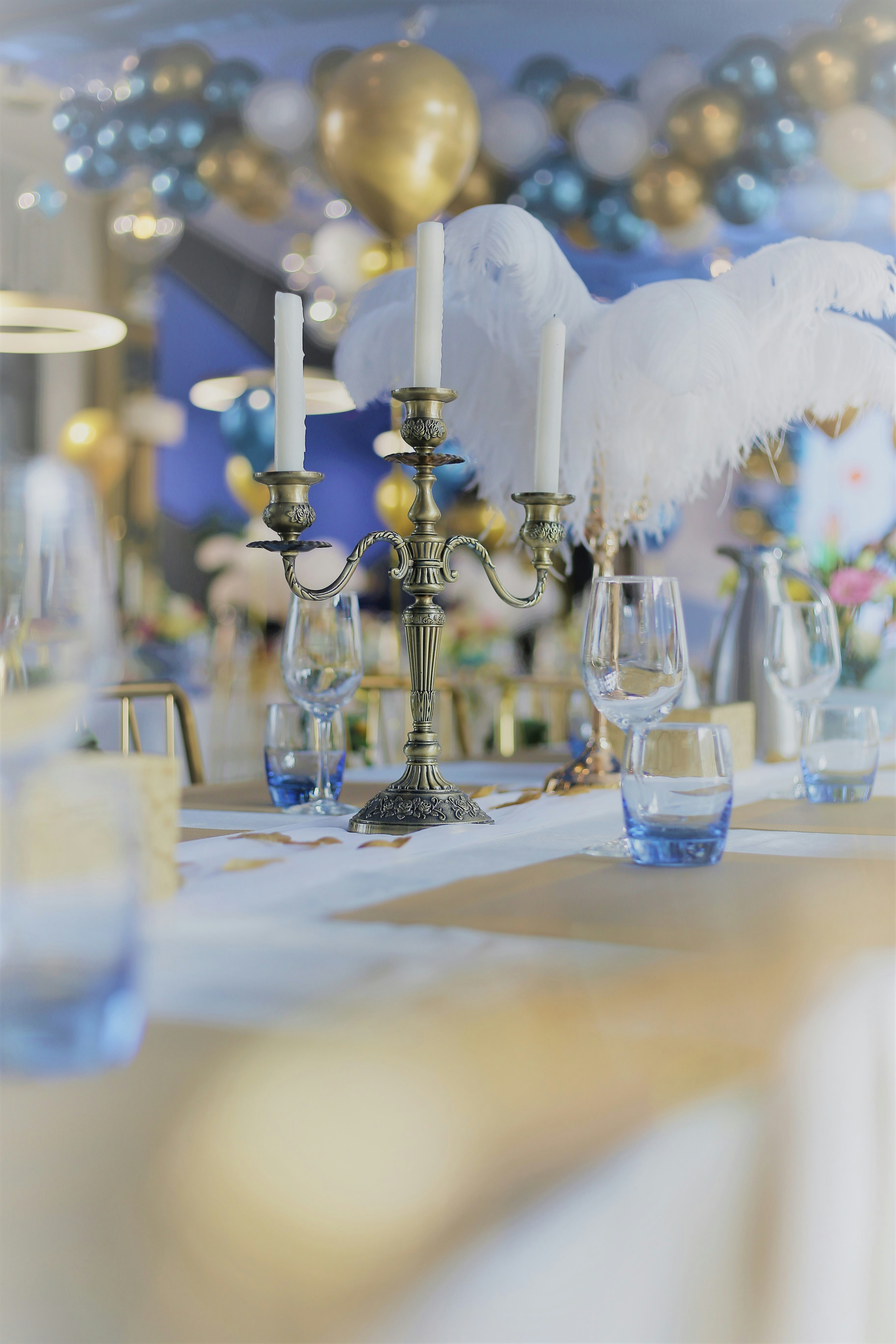 Candlelit centerpiece with feather flourish at a festive banquet