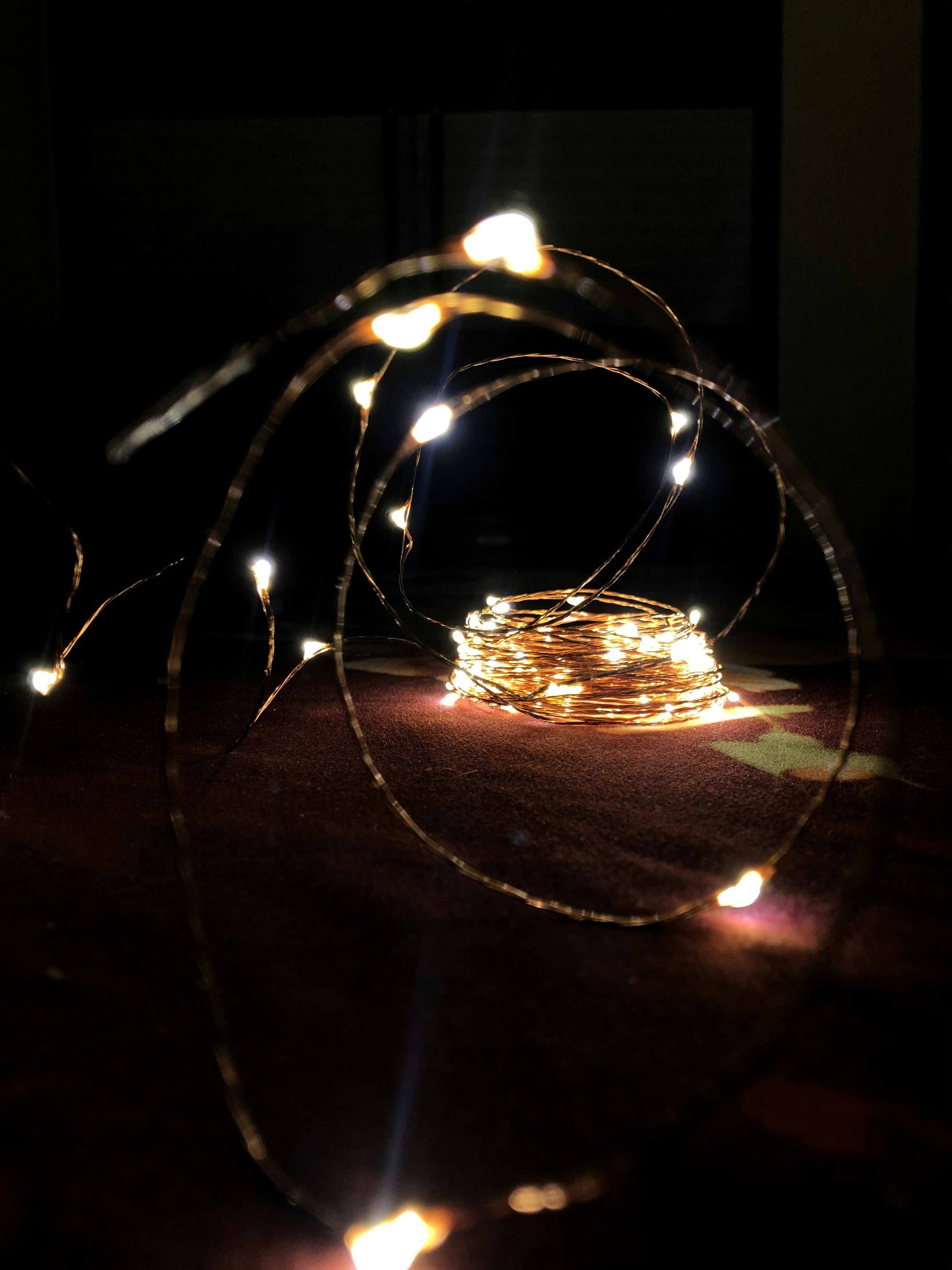 Delicate fairy lights spiraling on a surface, creating a warm glow against a dark background.