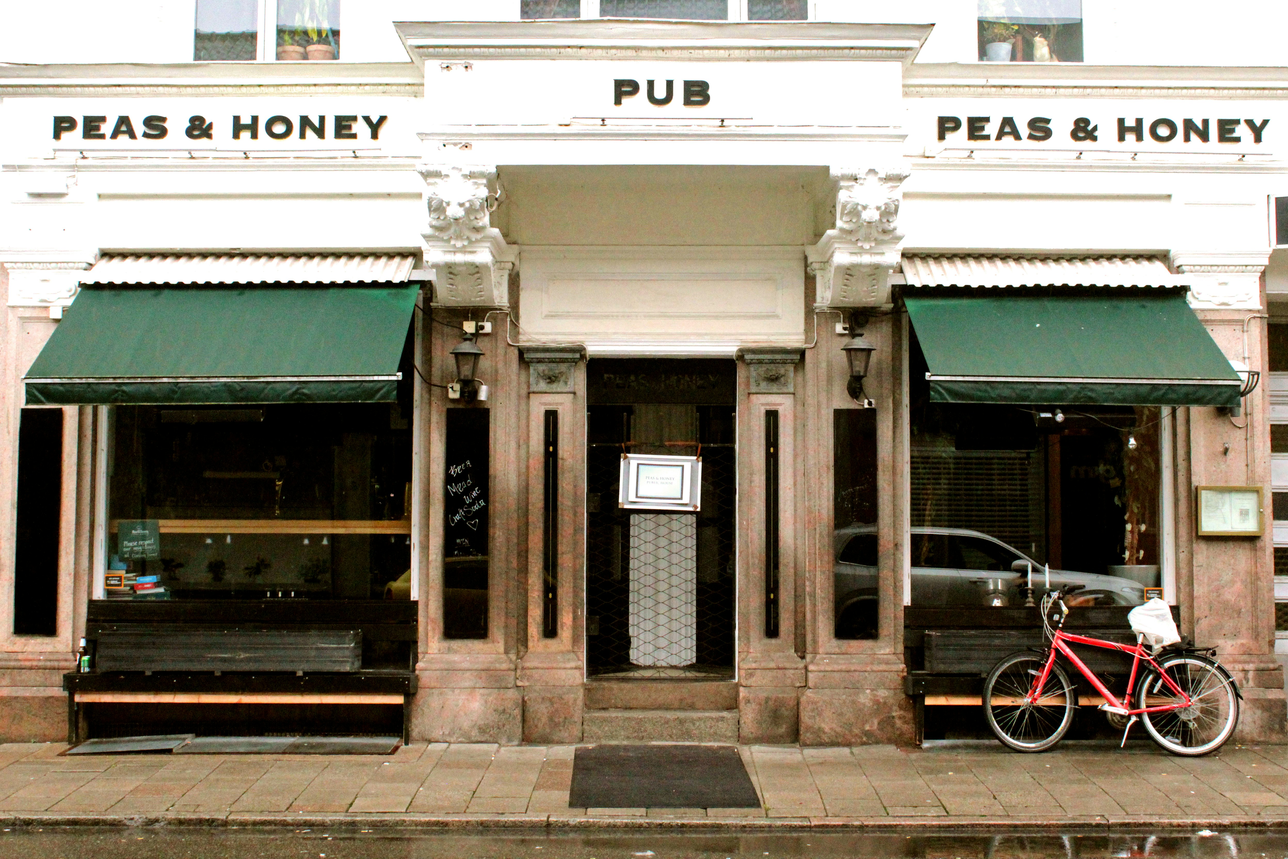 Old Pub Facade with Green Awnings and a Red Bicycle