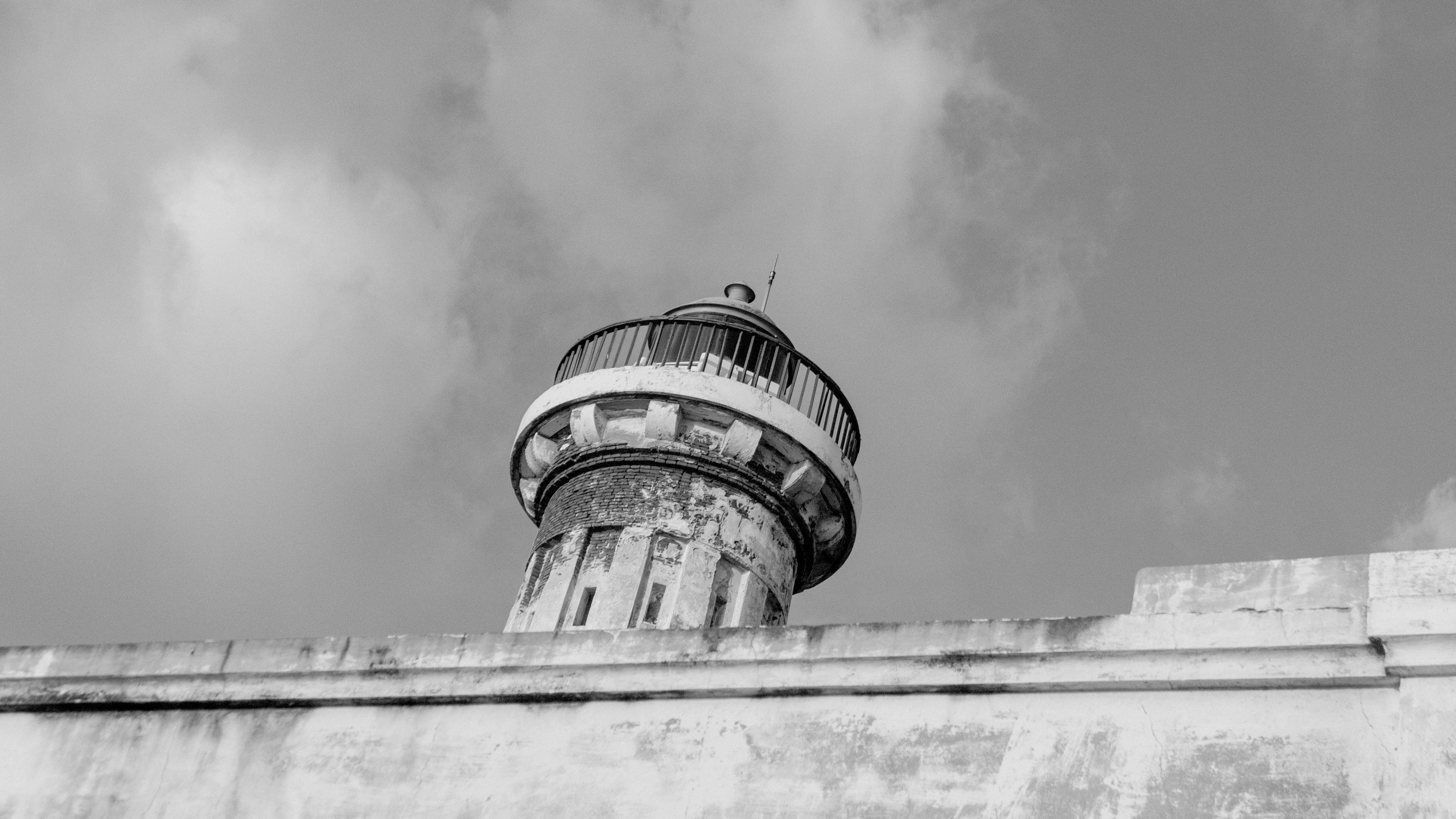 Historic lighthouse against a cloudy sky, captured in monochrome.