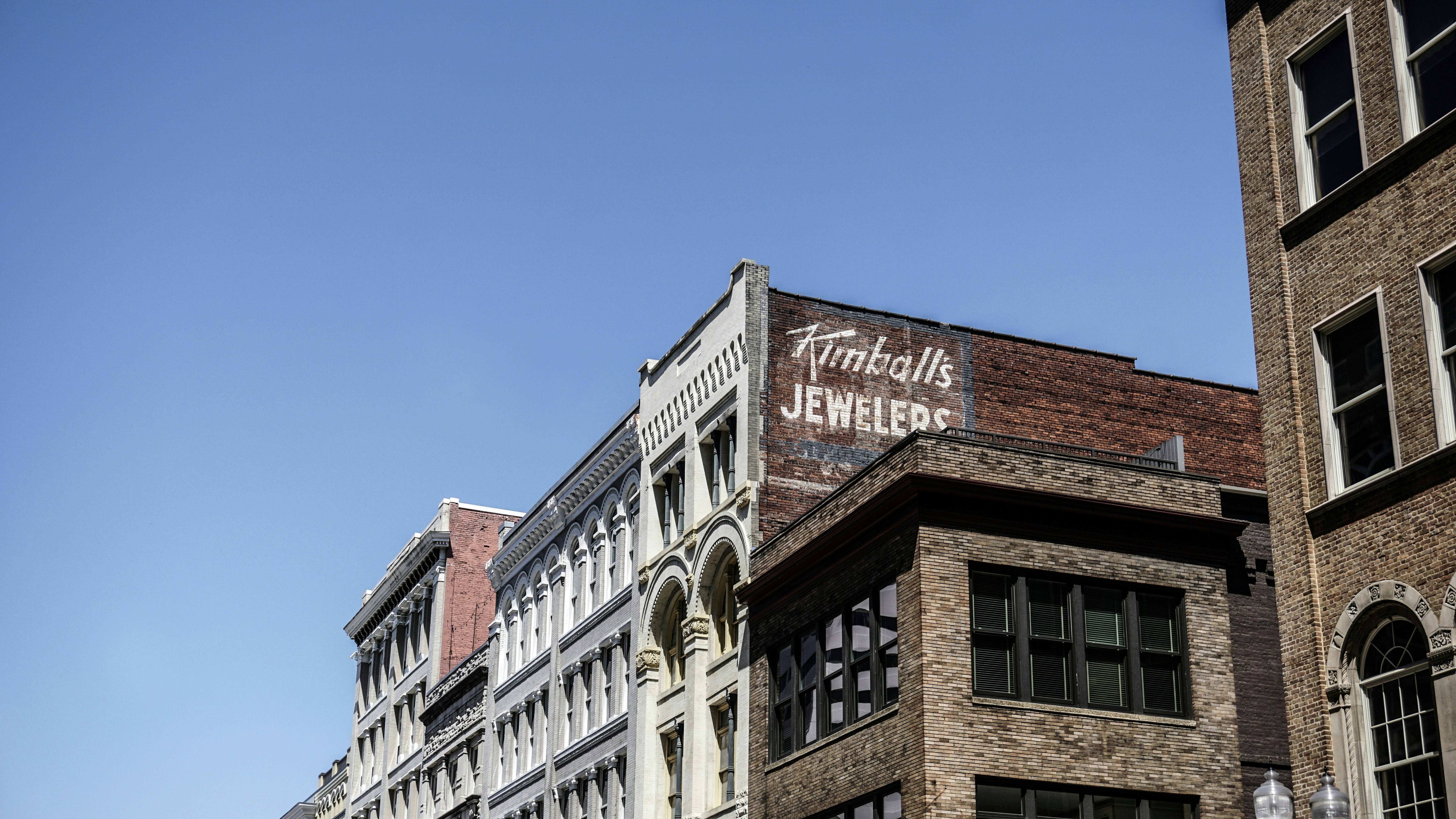 Historic brick buildings with worn signage under a bright blue sky.
