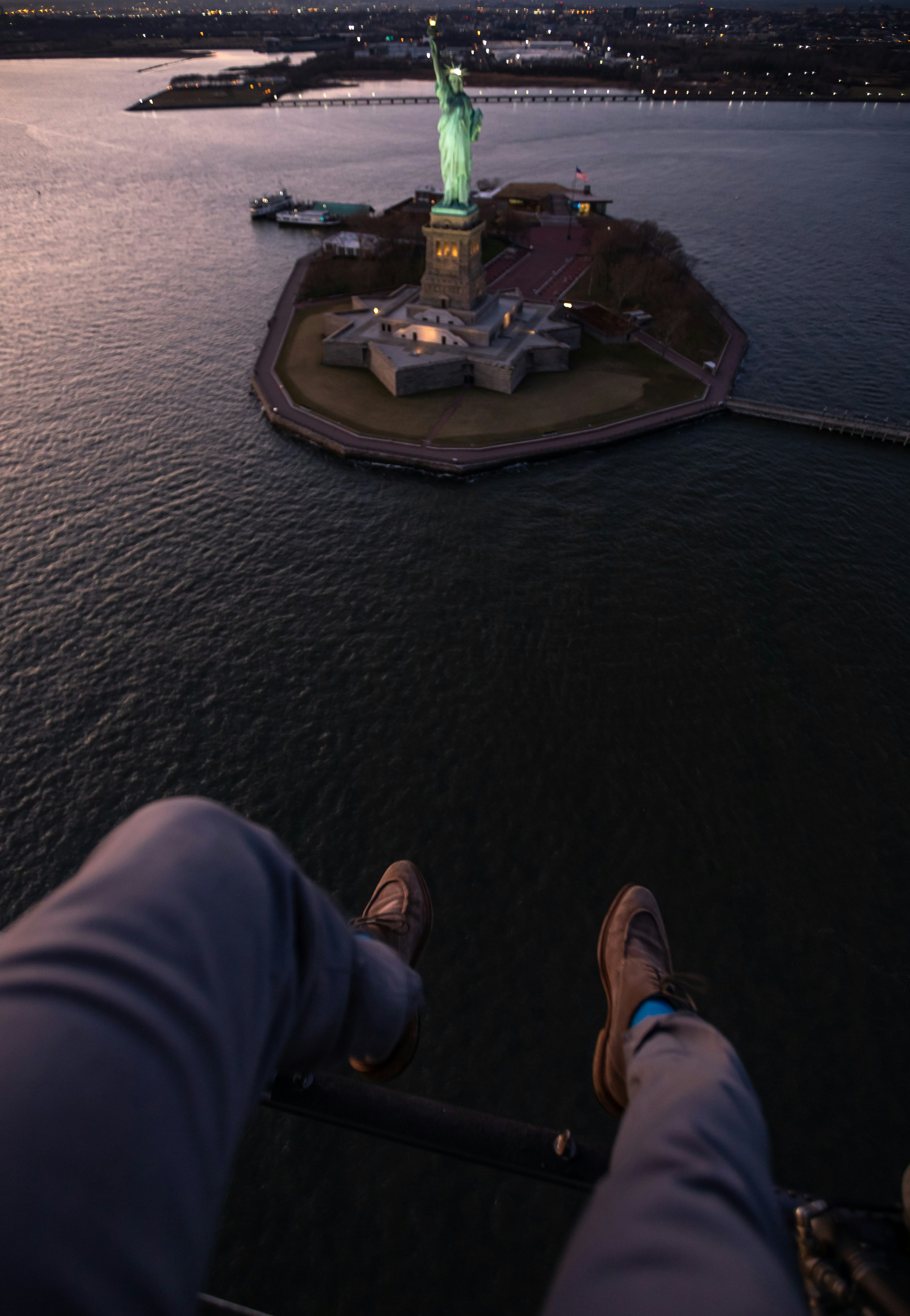 Person in black pants and blue flip flops sitting on brown wooden dock ...