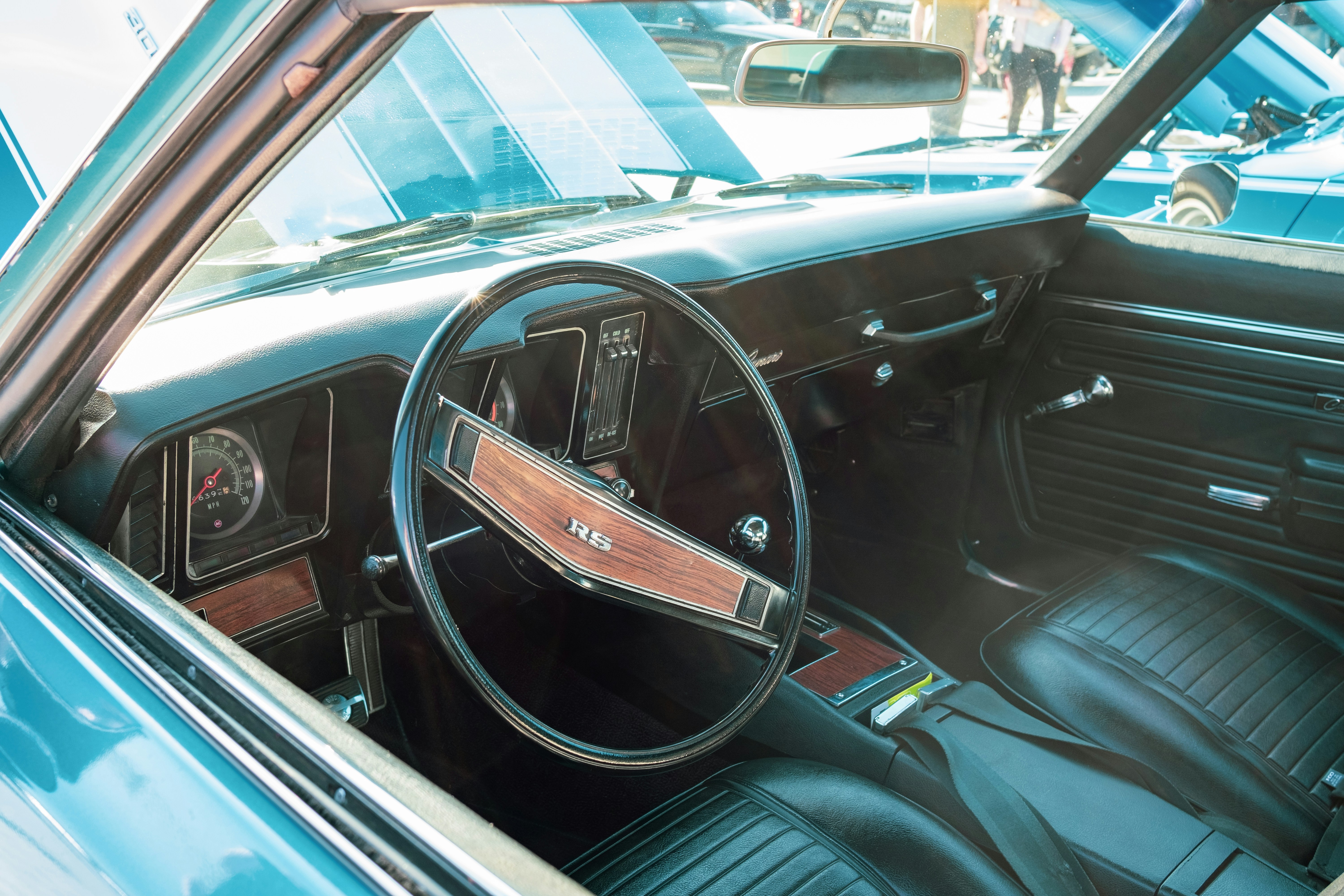 Interior view of a vintage car showcasing a wooden steering wheel and leather seats, reflecting classic automotive design.