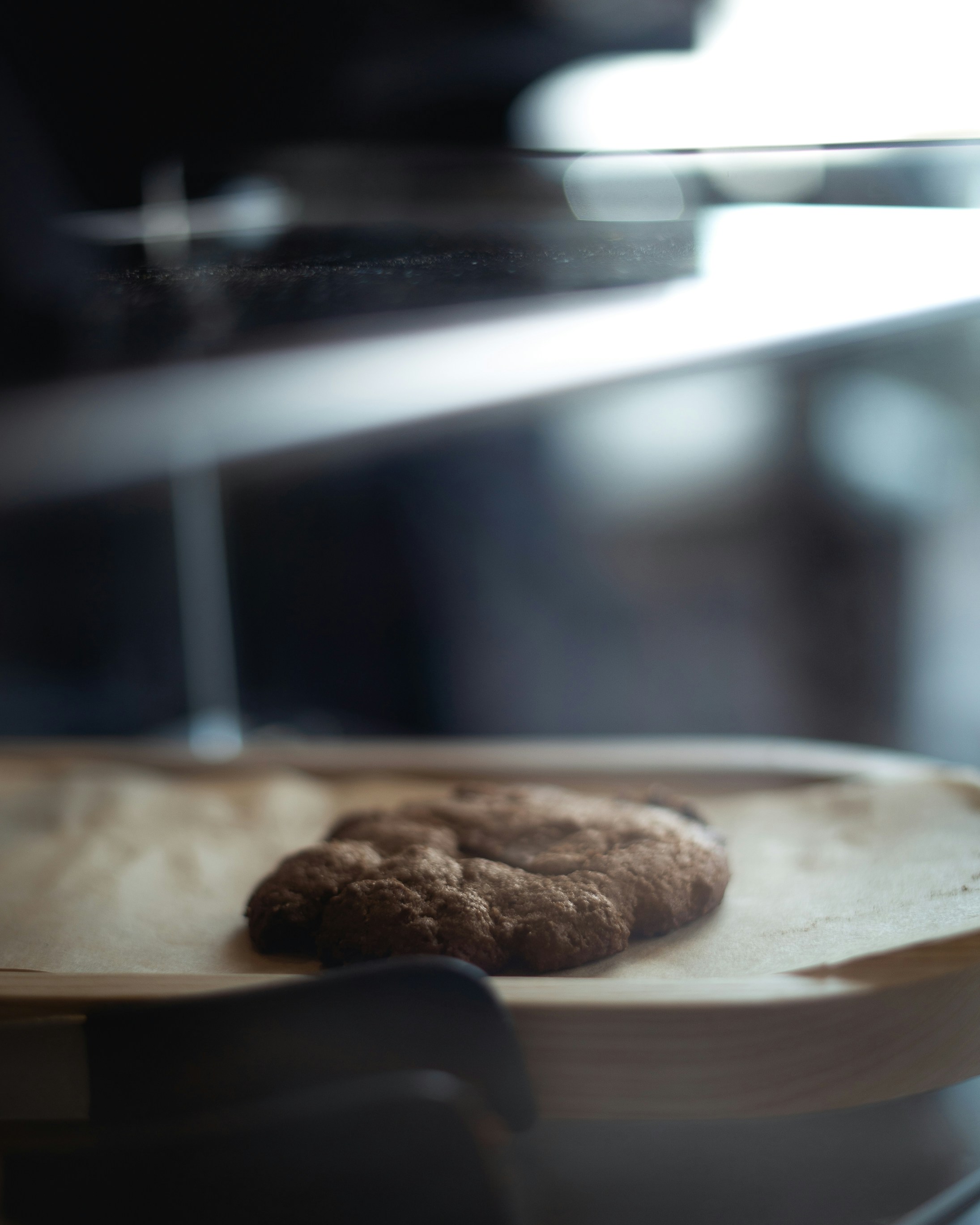 Soft Focus Chocolate Cookie on Parchment: Quiet Bake Behind Dim Oven Glass