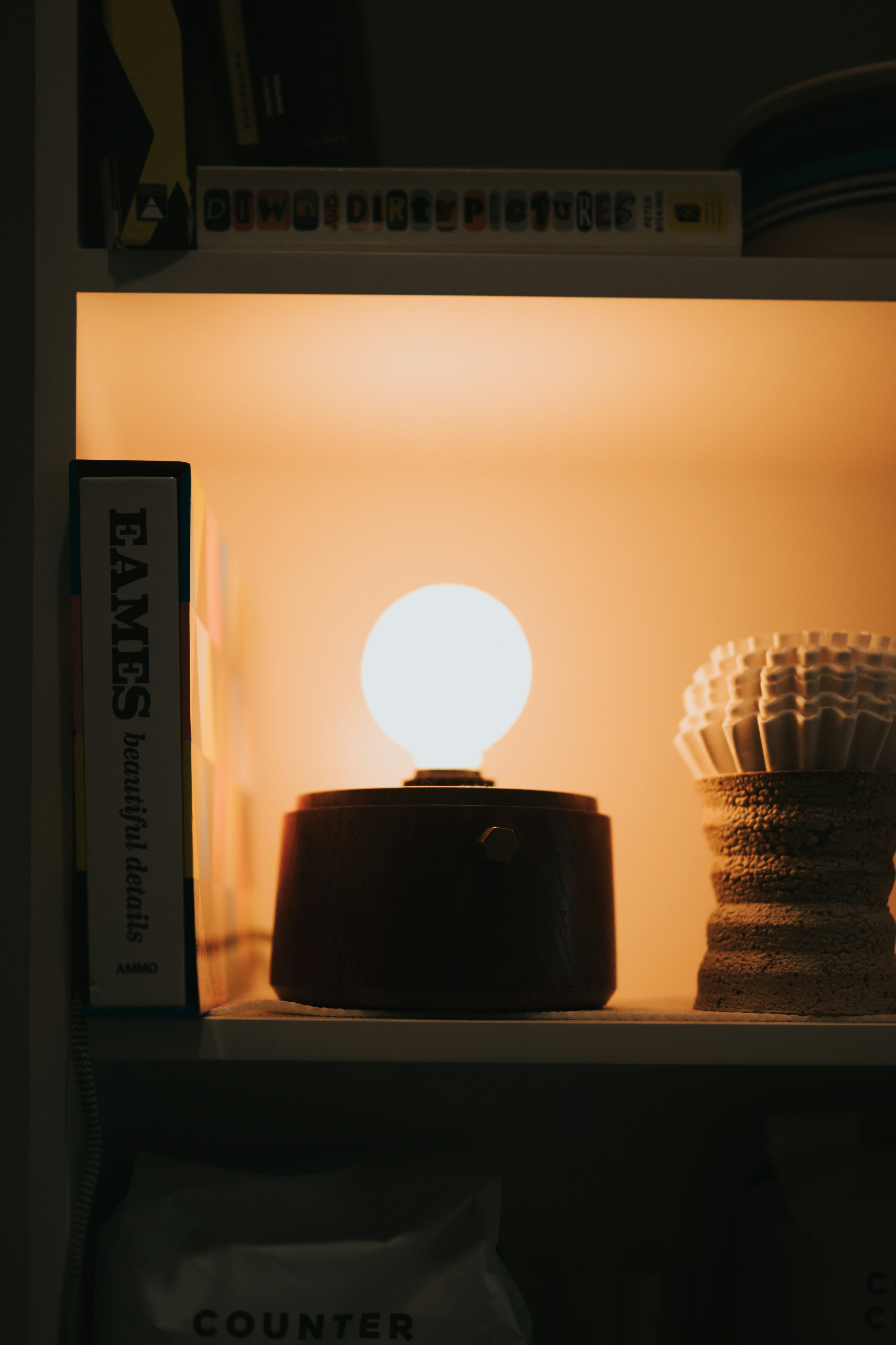 Ambient Centerpiece: A Soft-Glow Bulb Framed by Books and Textured Stacks