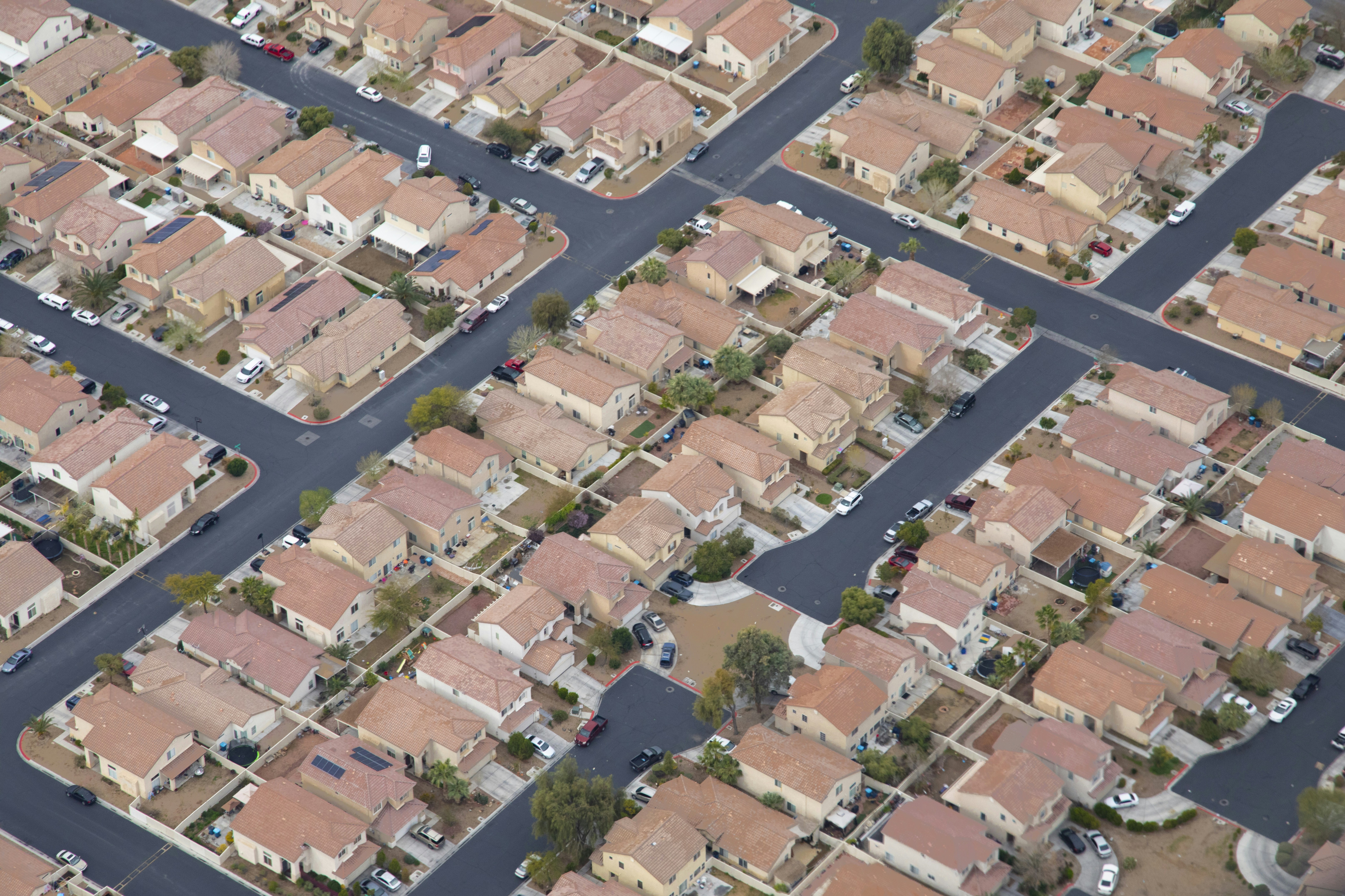 Aerial view of a suburban neighborhood showcasing a grid of residential homes and streets. The arrangement highlights the uniformity and structure of modern housing developments.