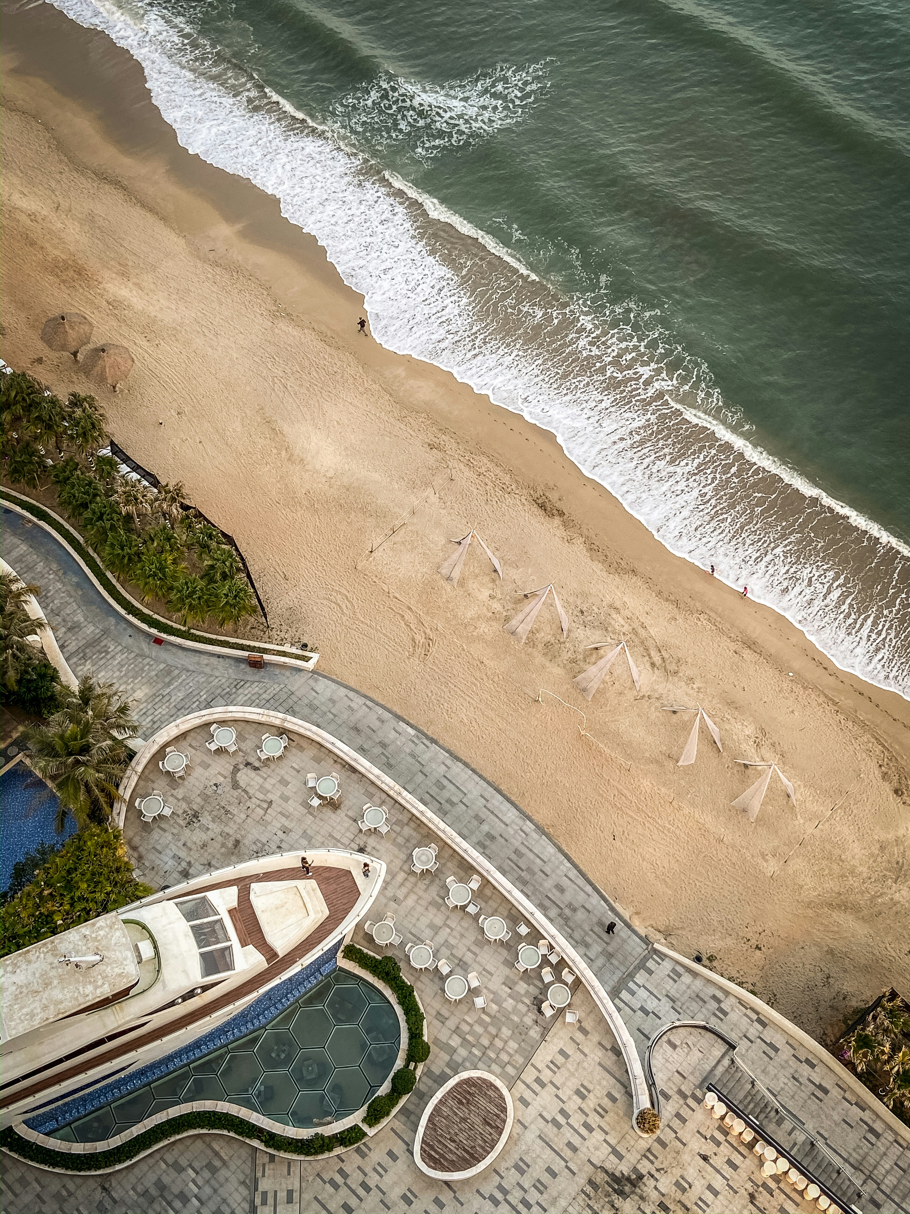 Serpentine Terrace Meets the Seashore: An Aerial View of a Curved Pool by the Beach
