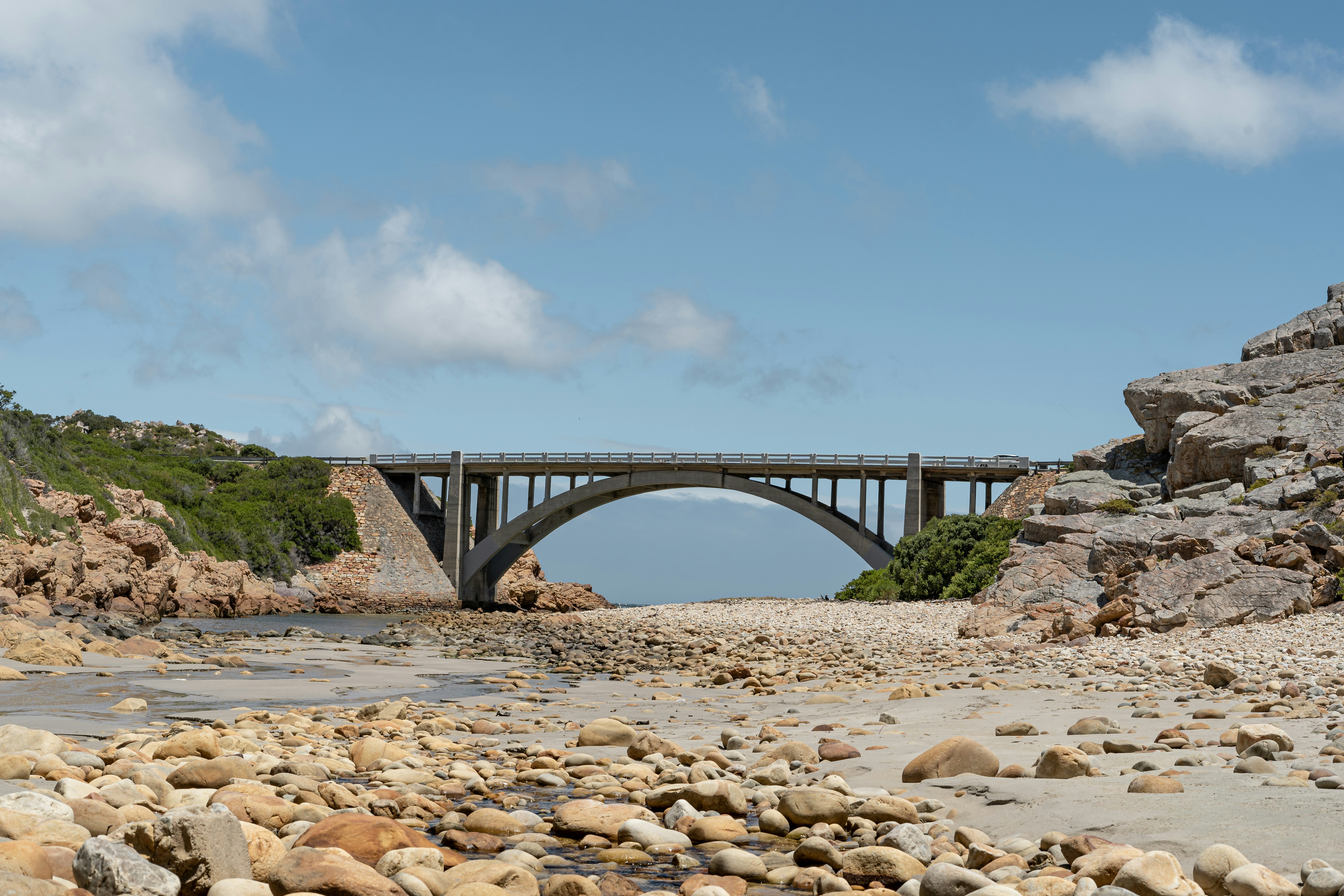 Arch Over Pebbles: Coastal Bridge Framed by Sea and Sky