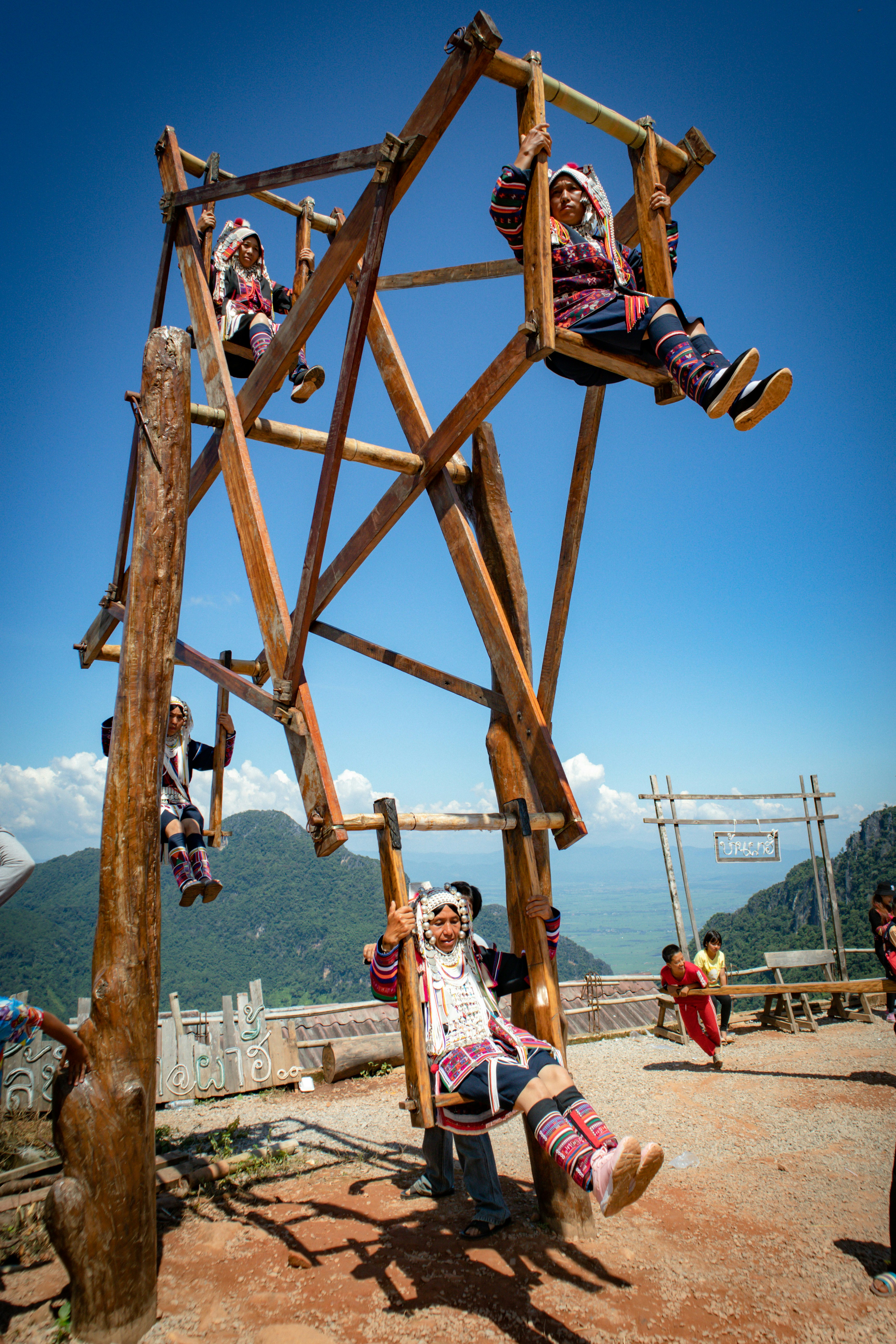 Children on a towering wooden swing structure against a clear mountain backdrop