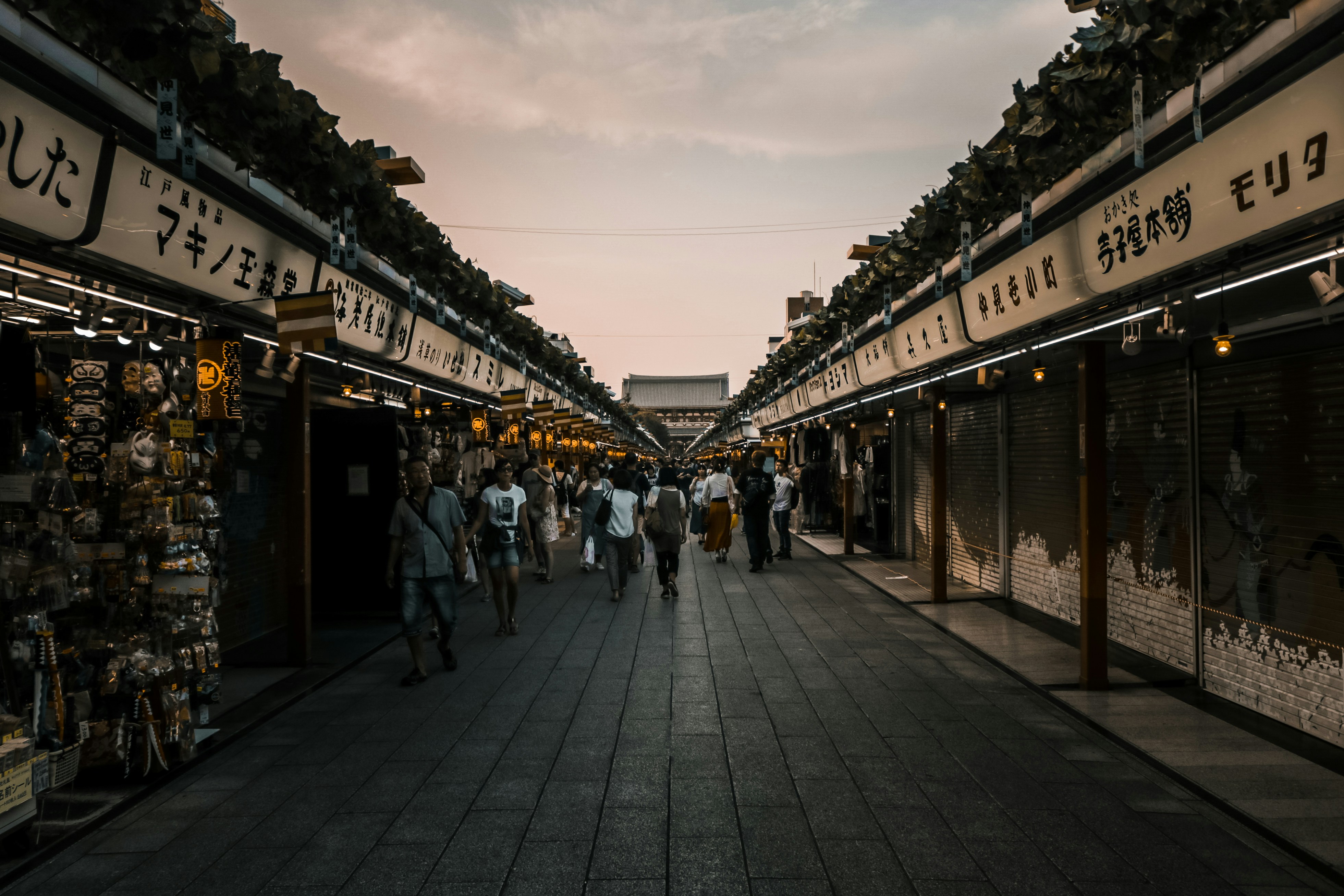 Bustling market street lined with shops and illuminated signs, capturing the essence of evening commerce. A diverse crowd explores the vibrant offerings.