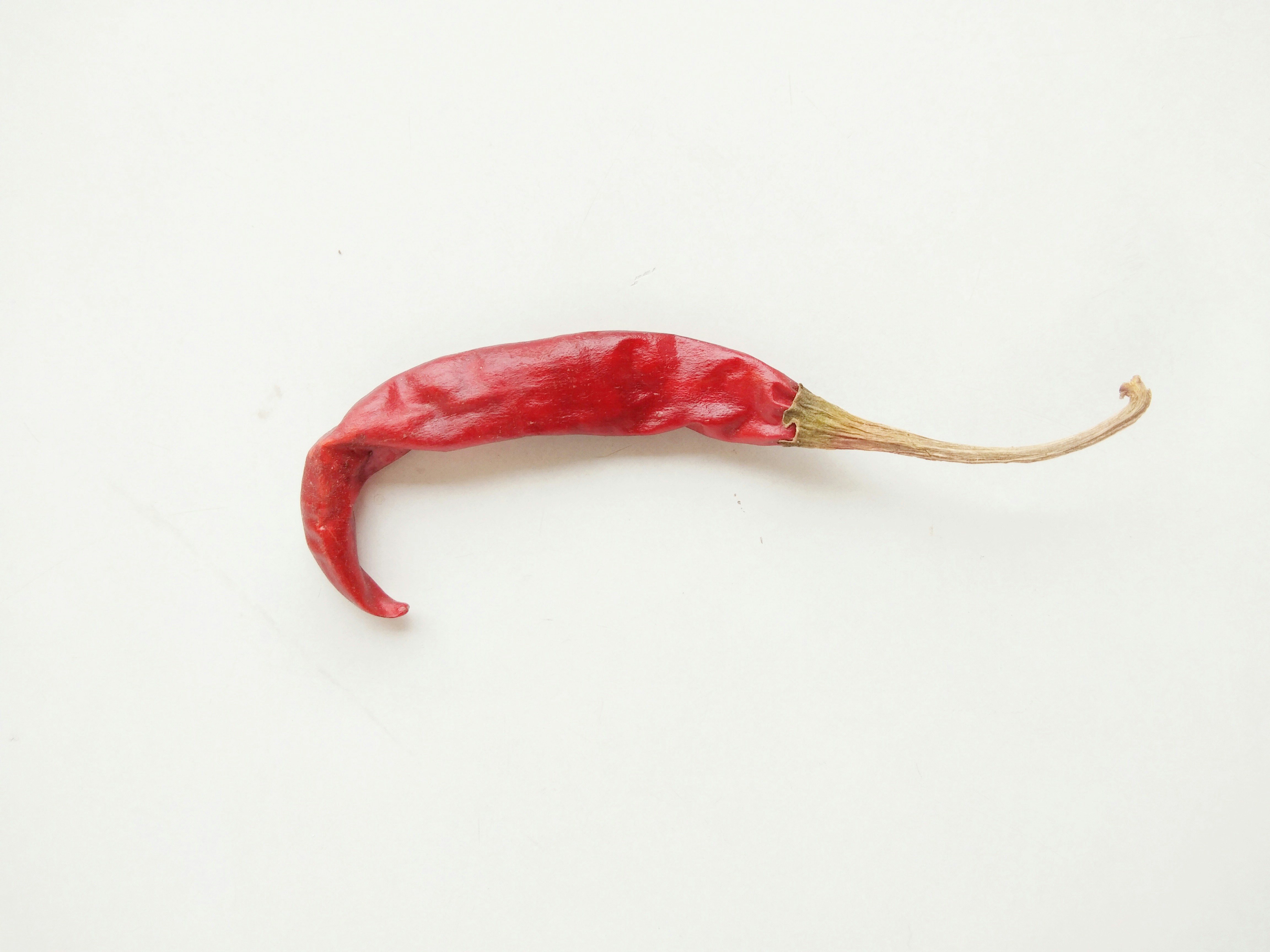 Scarlet Curve on White: Minimalist Pepper Still-Life