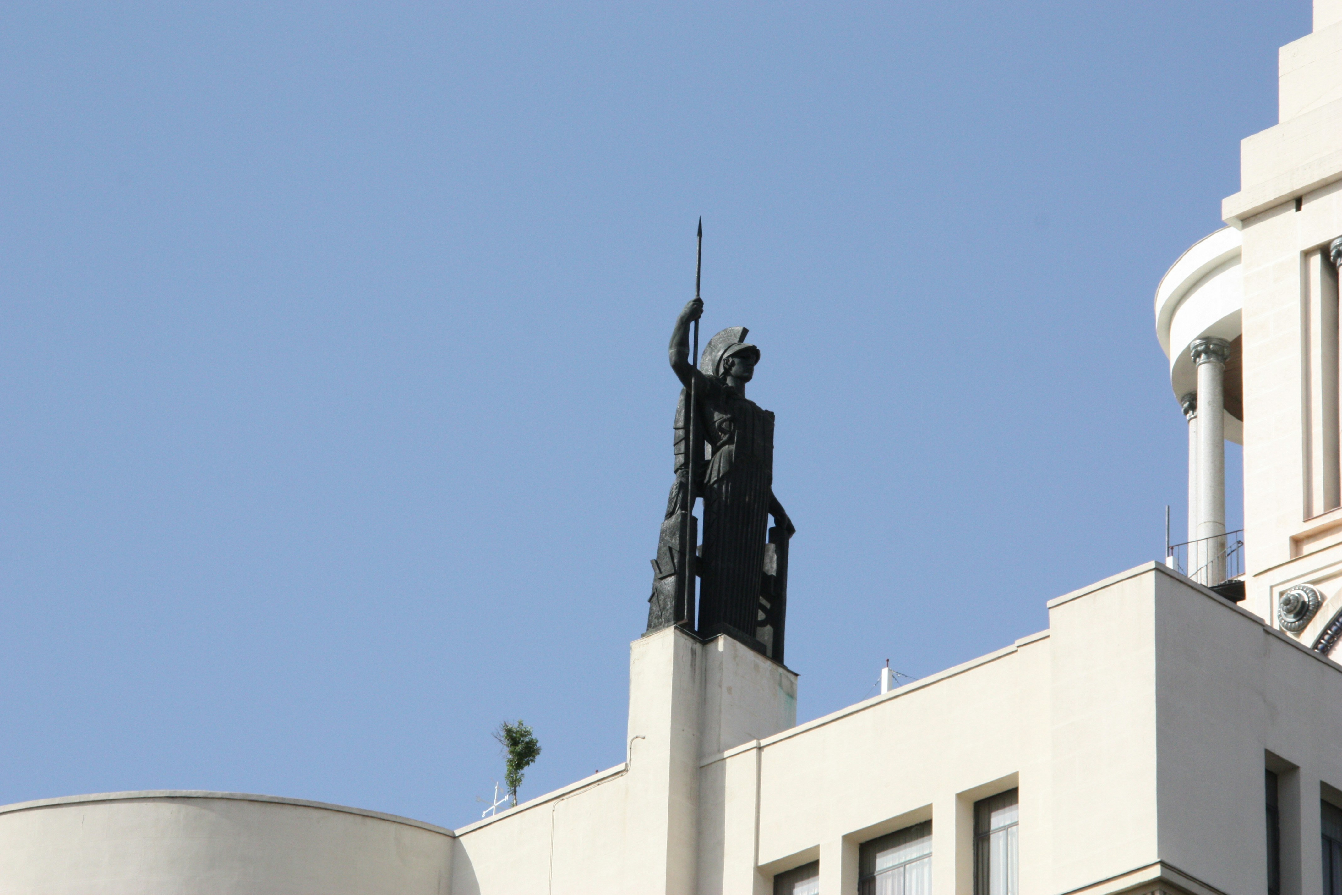 Stone Sentinel Over a White Facade Beneath a Perfectly Clear Sky