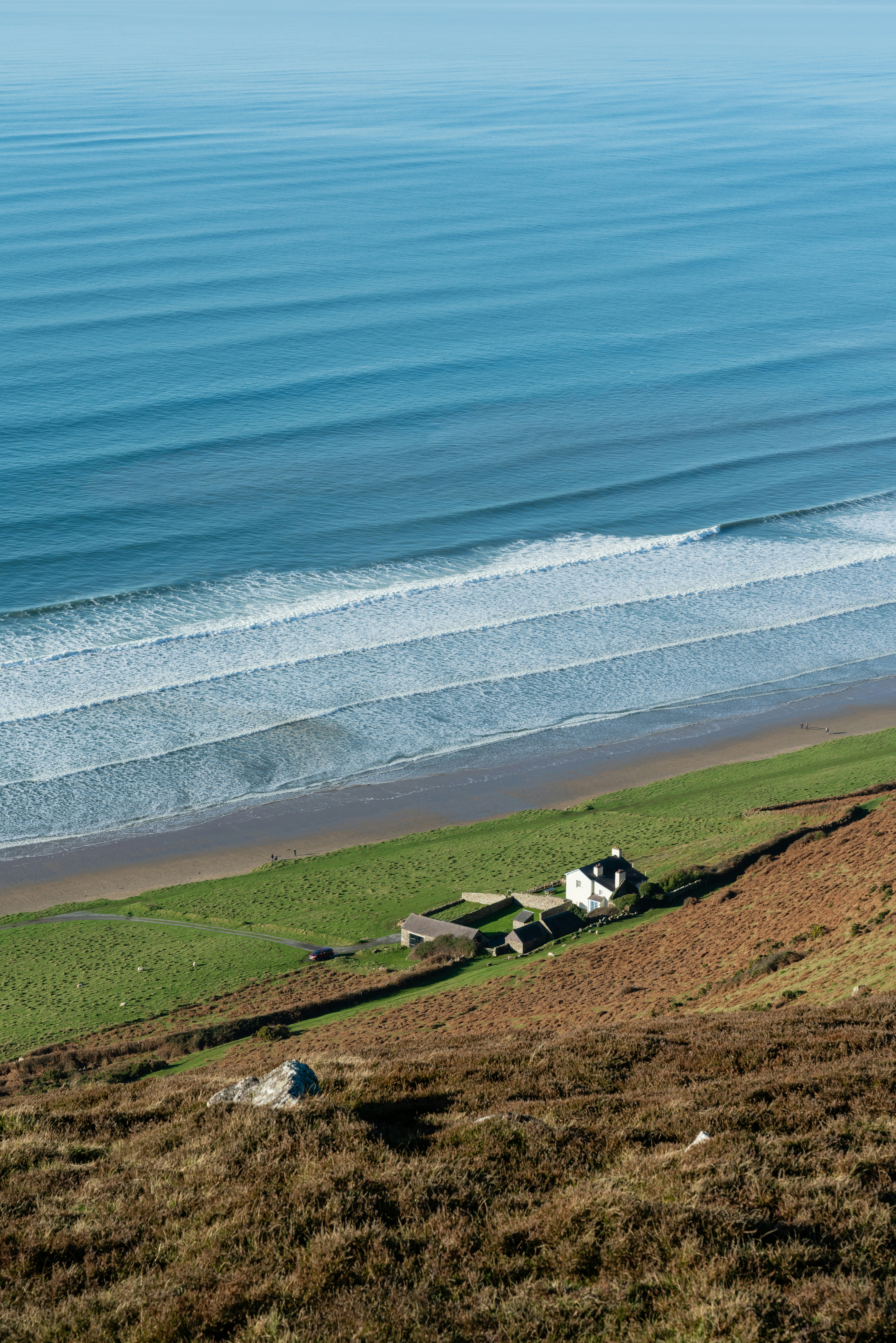 Quaint coastal cottages nestled against a backdrop of rolling waves and lush green hills. The scene captures the tranquility of a seaside escape.