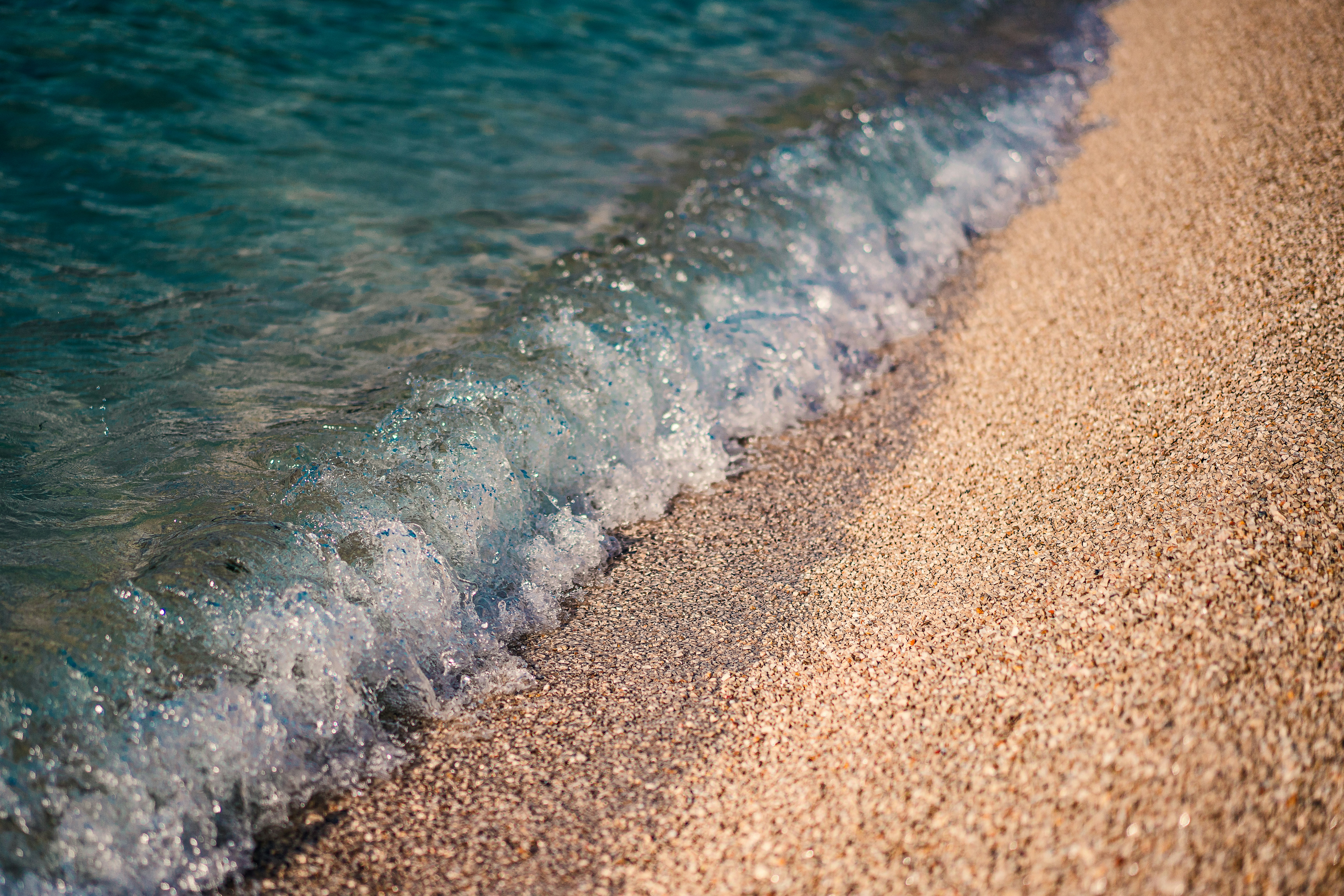 Pebble-Textured Shoreline: Waves Whisper Against a Sunlit Beach