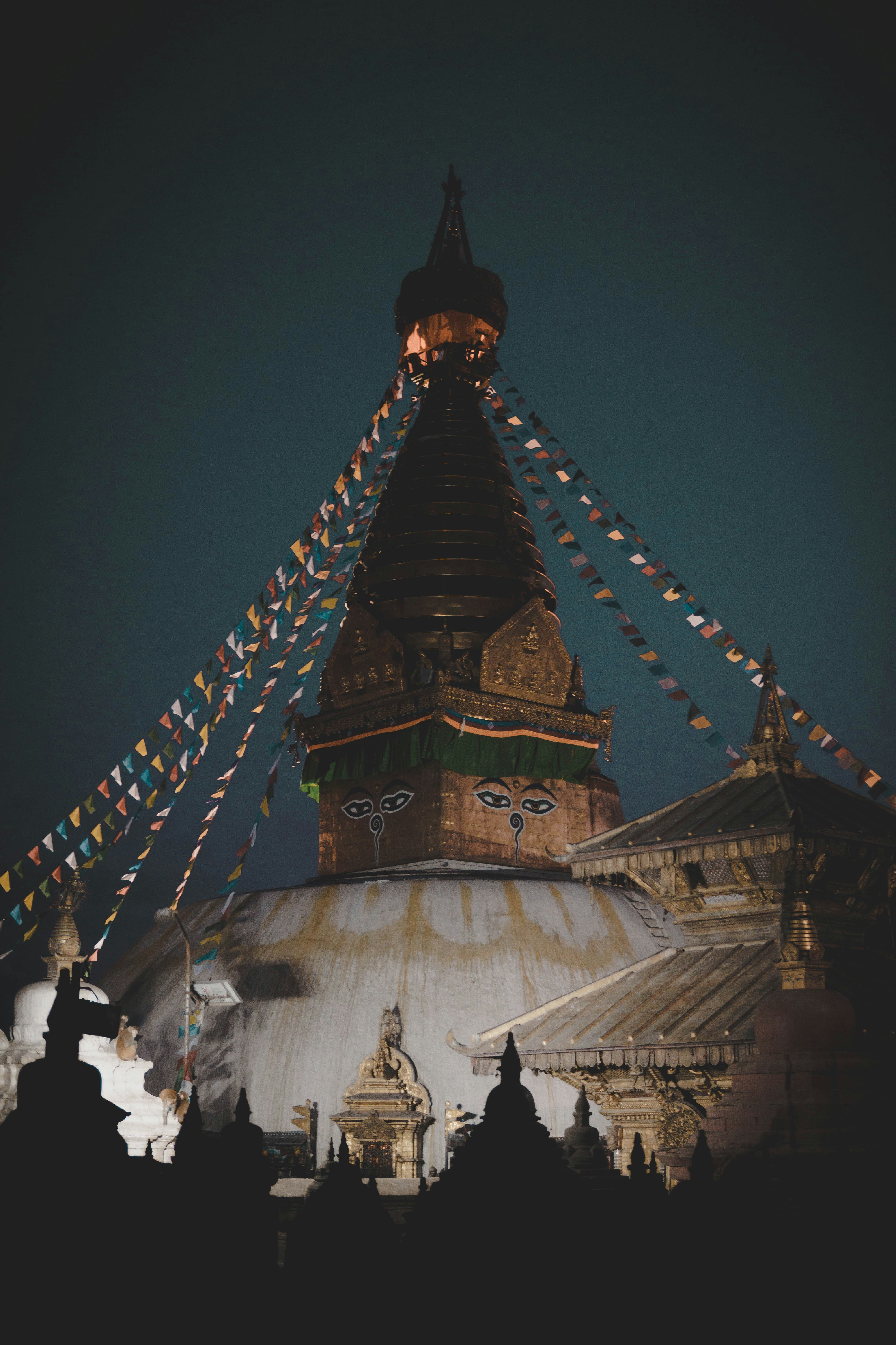 The iconic stupa adorned with prayer flags stands against the twilight sky, showcasing intricate details and spiritual significance.