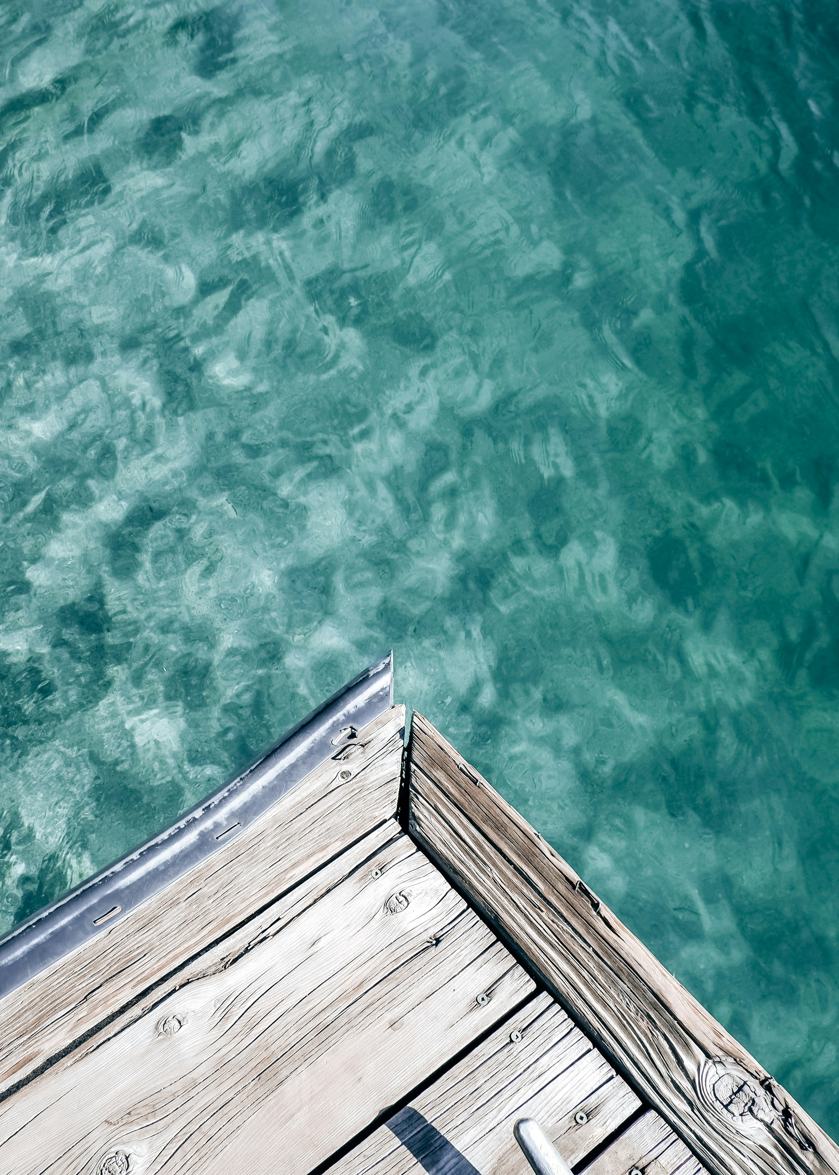 Weathered wooden dock extending into crystal-clear water, reflecting the tranquil beauty of nature.