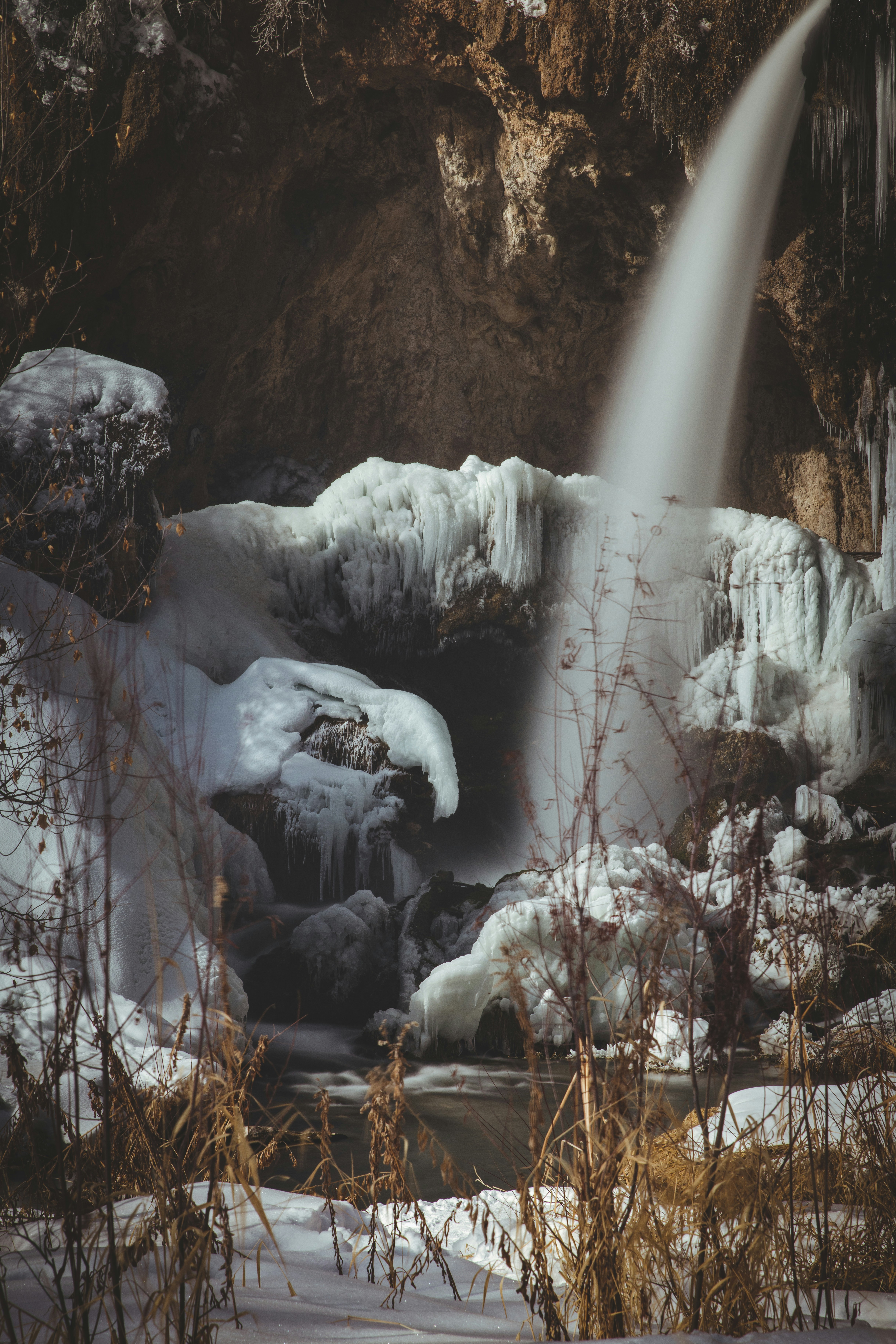 Icefall at the Edge: A Winter Cascade Framed by Quiet Grasses