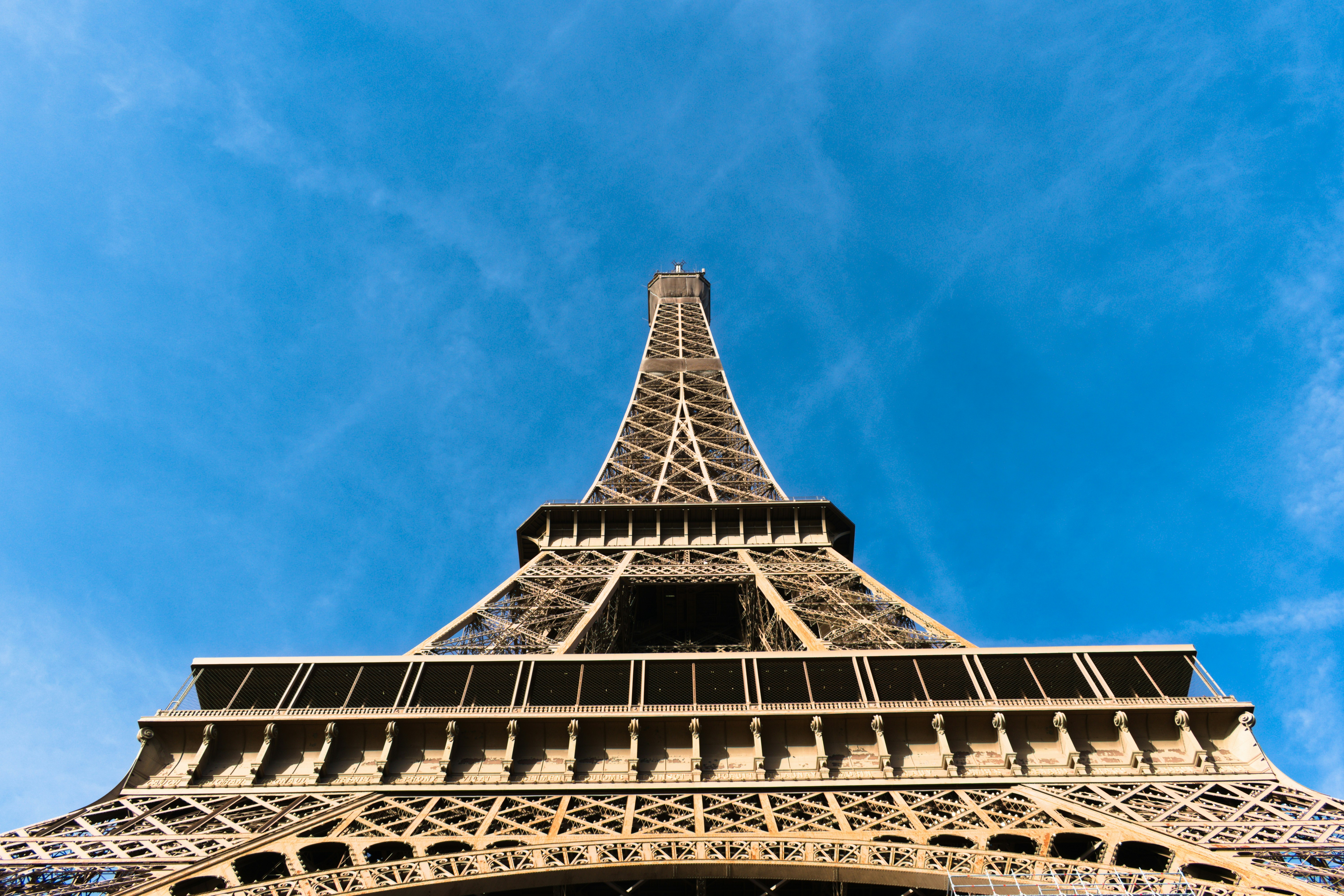 Low angle shot of the Eiffel Tower against a clear blue sky.