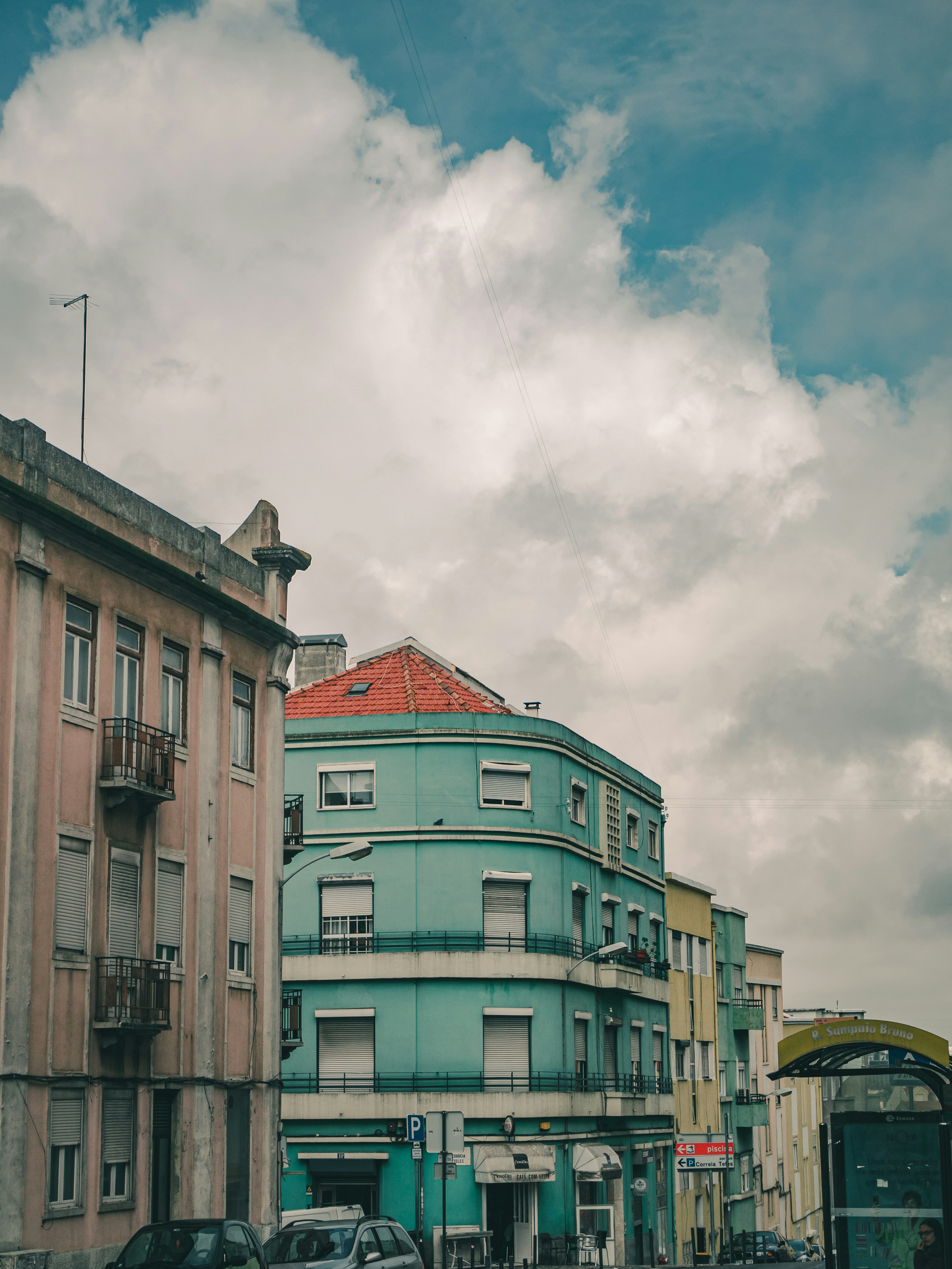 Colorful buildings line a city street under a dynamic sky, showcasing architectural diversity. The scene captures the essence of urban life.