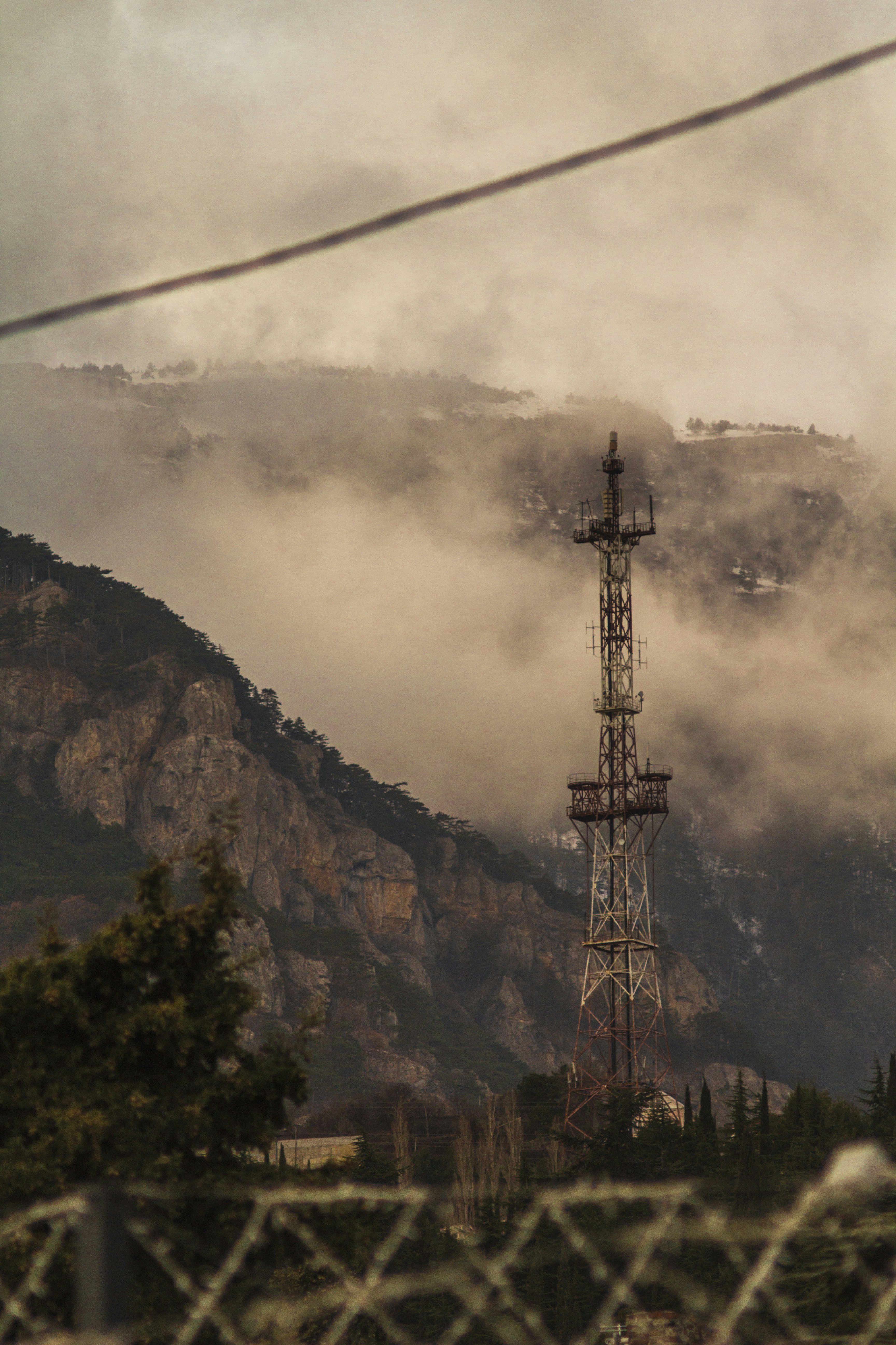 Mast in the Mist: a fog-wrapped hillside under a quiet sky