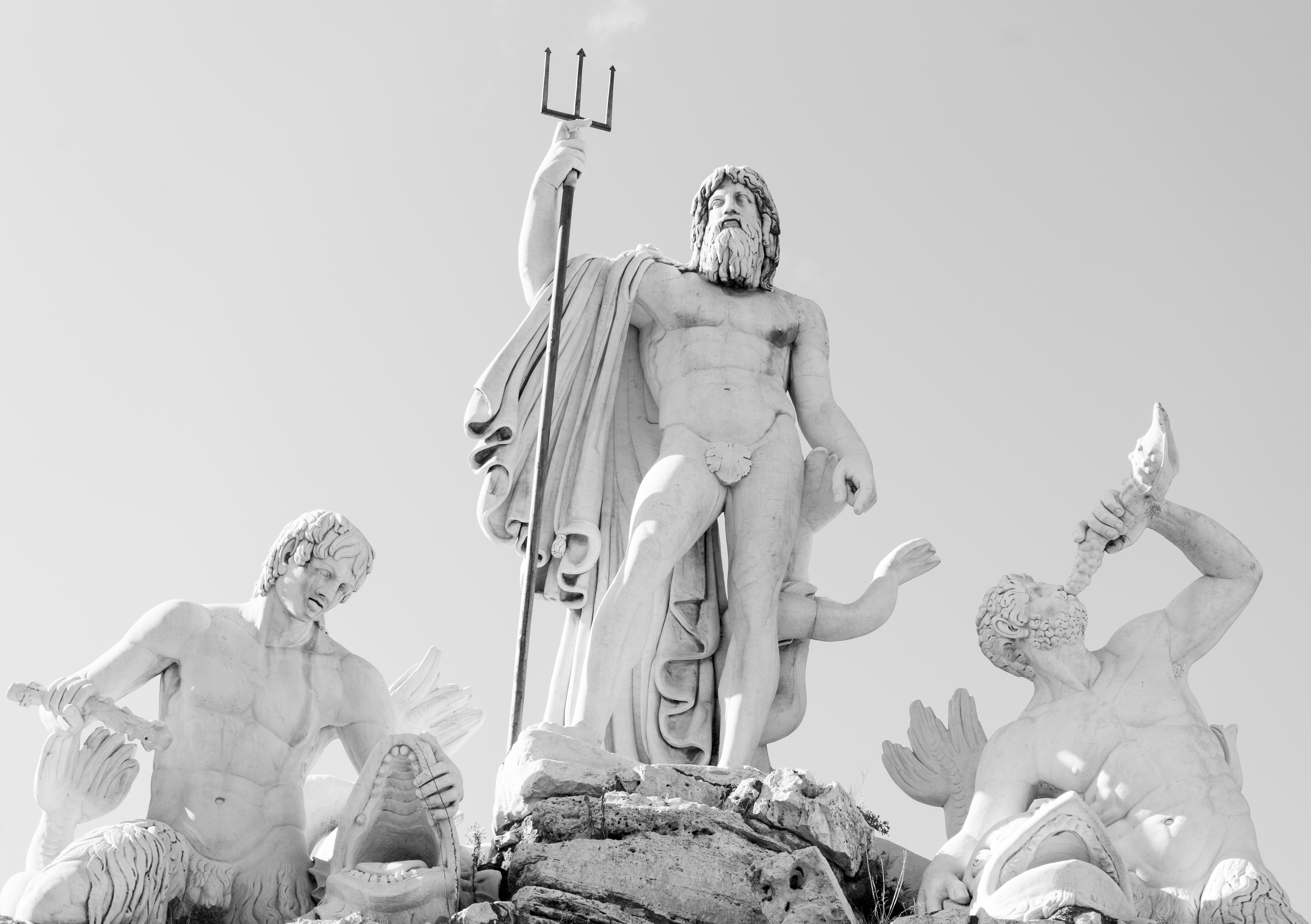 Marble statues of Poseidon and companions against a clear sky.