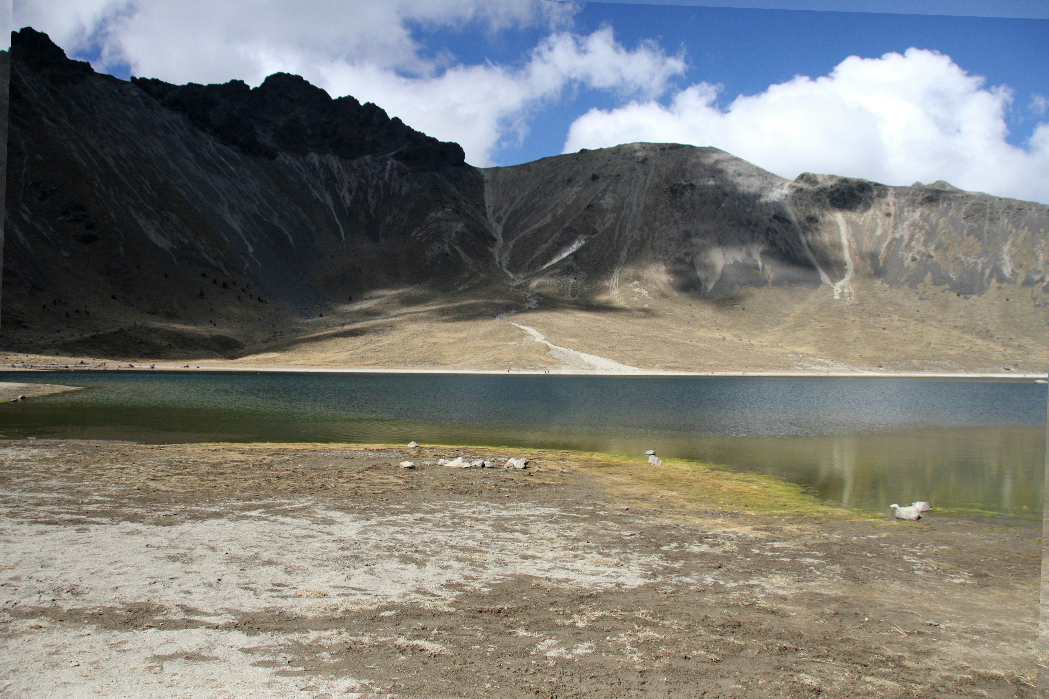Serene mountain lake with rocky terrain and clear blue sky in the background.