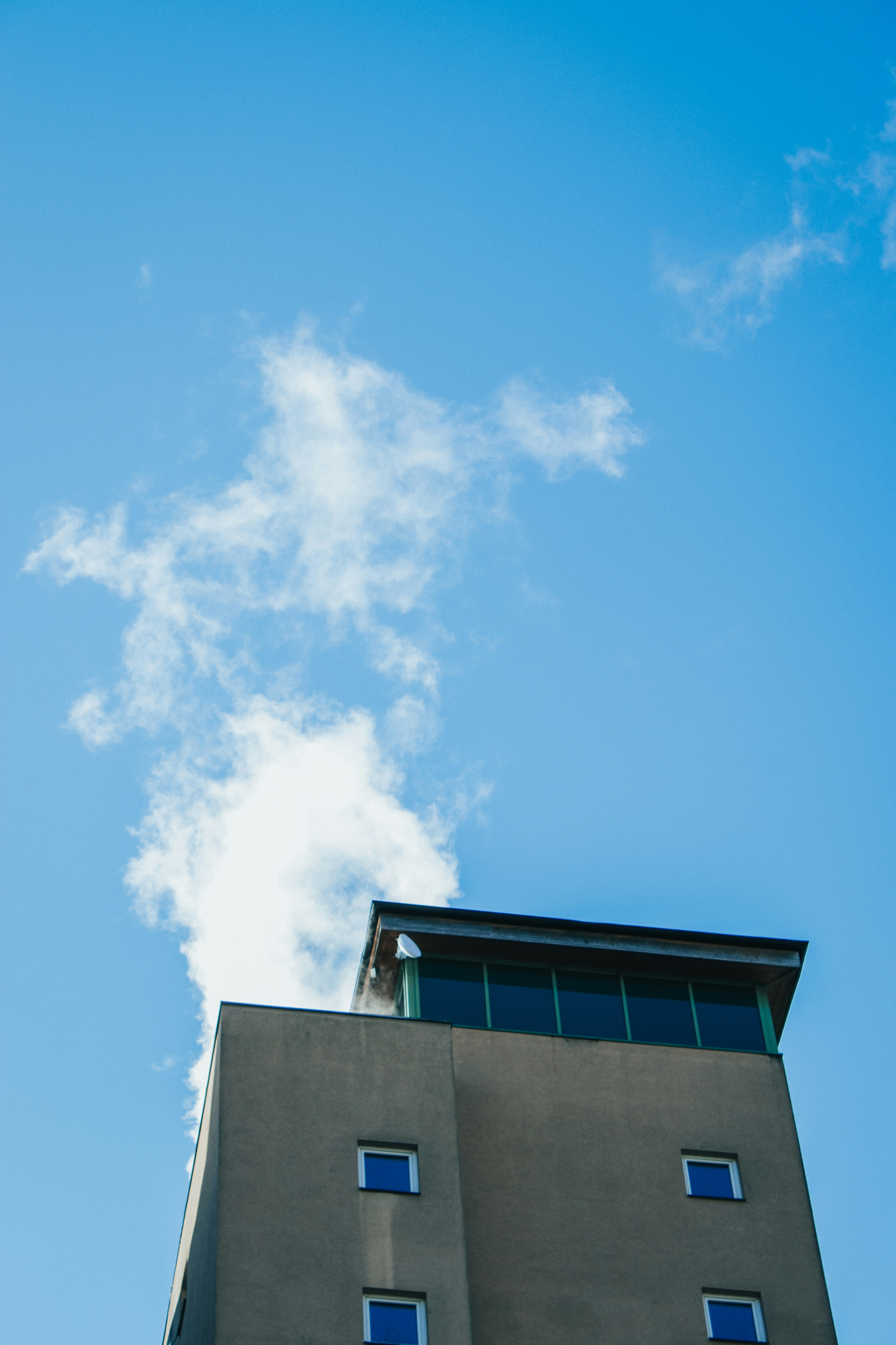 Blue Expanse over a Minimalist Tower, Smoke Curling from the Roof