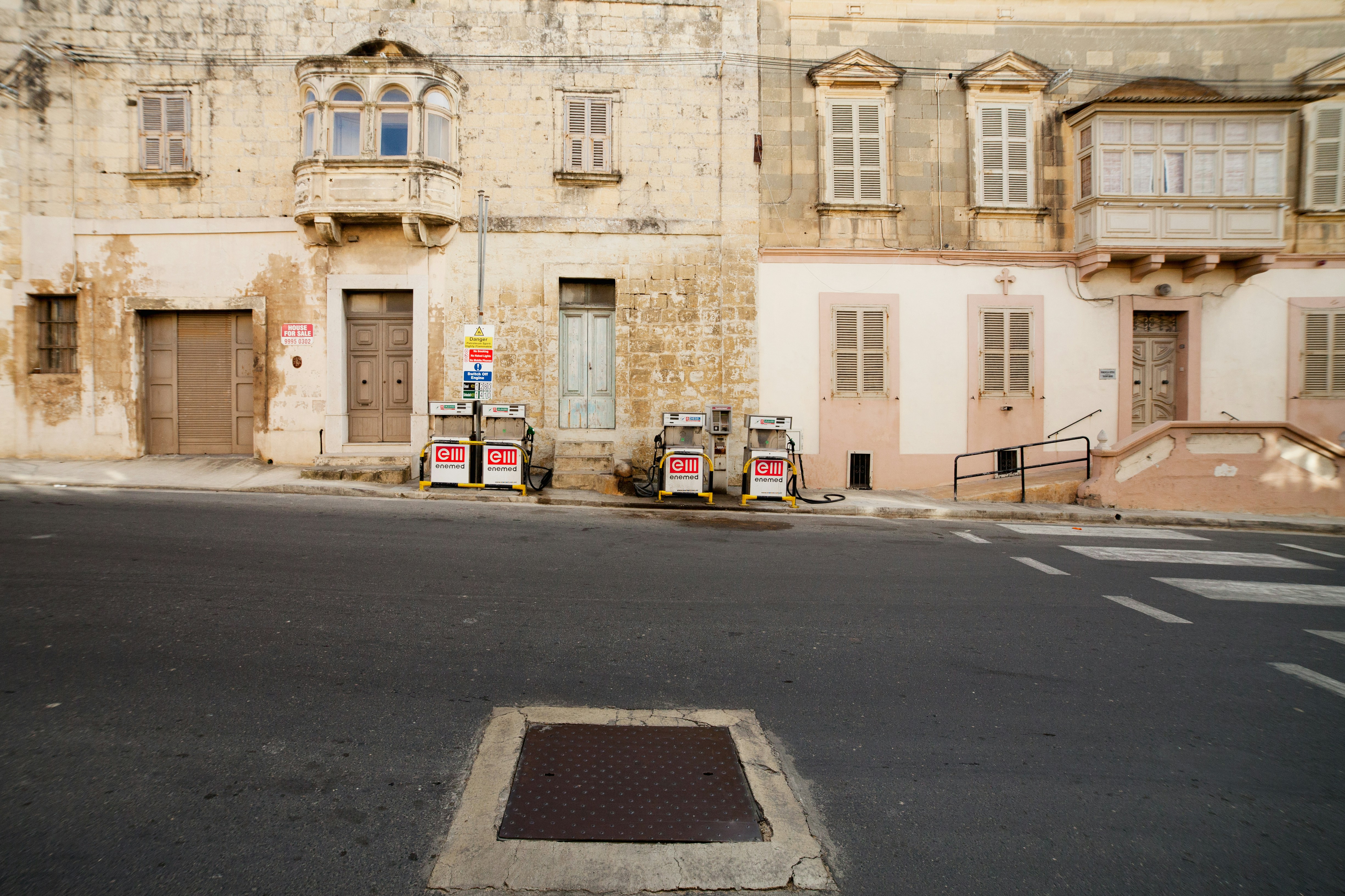 Historic buildings with weathered facades line a quiet street in Valletta, showcasing the architectural charm of Malta. A row of vintage parking meters adds a touch of nostalgia.