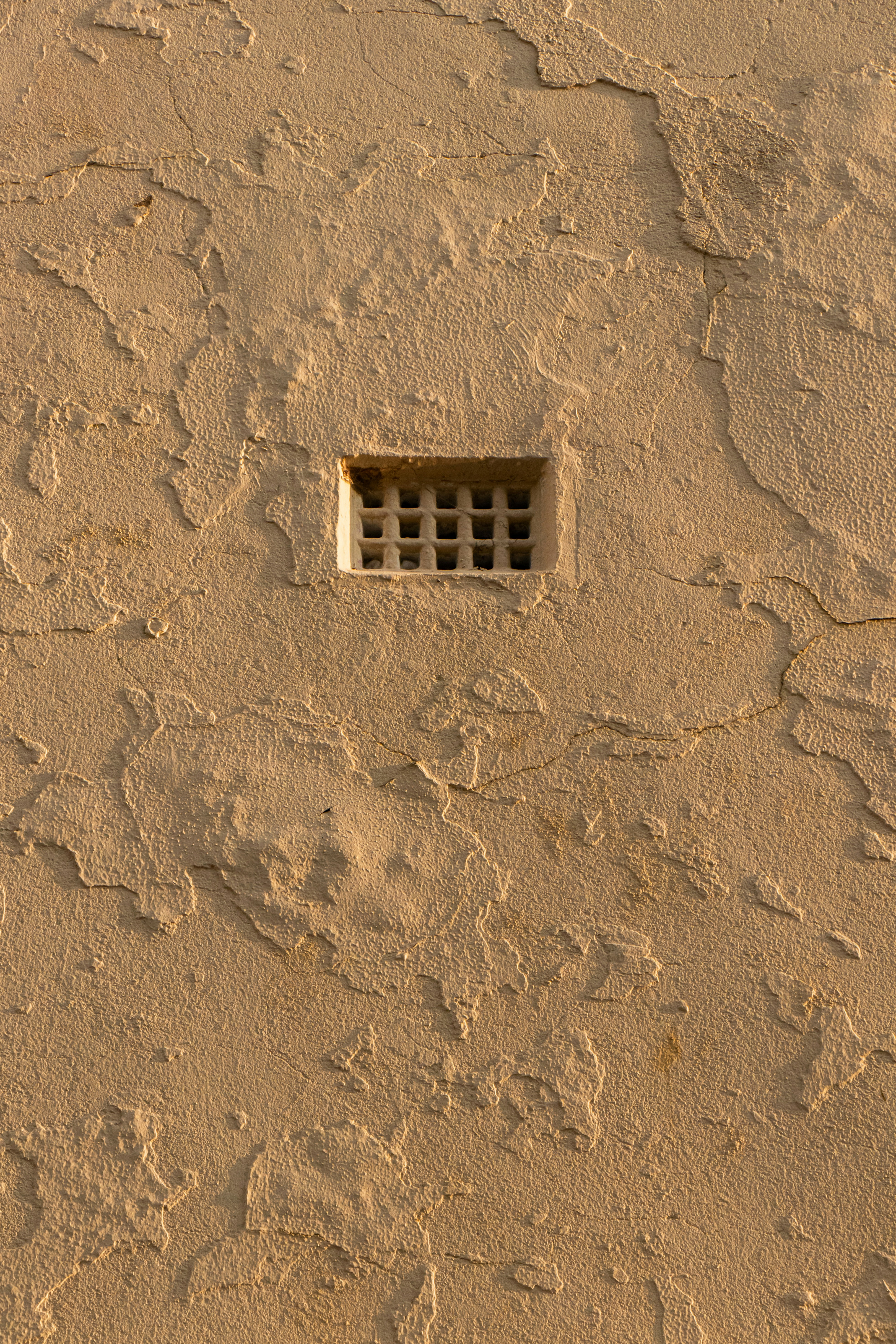 Vent Grid in a Sun-Warmed Adobe Wall