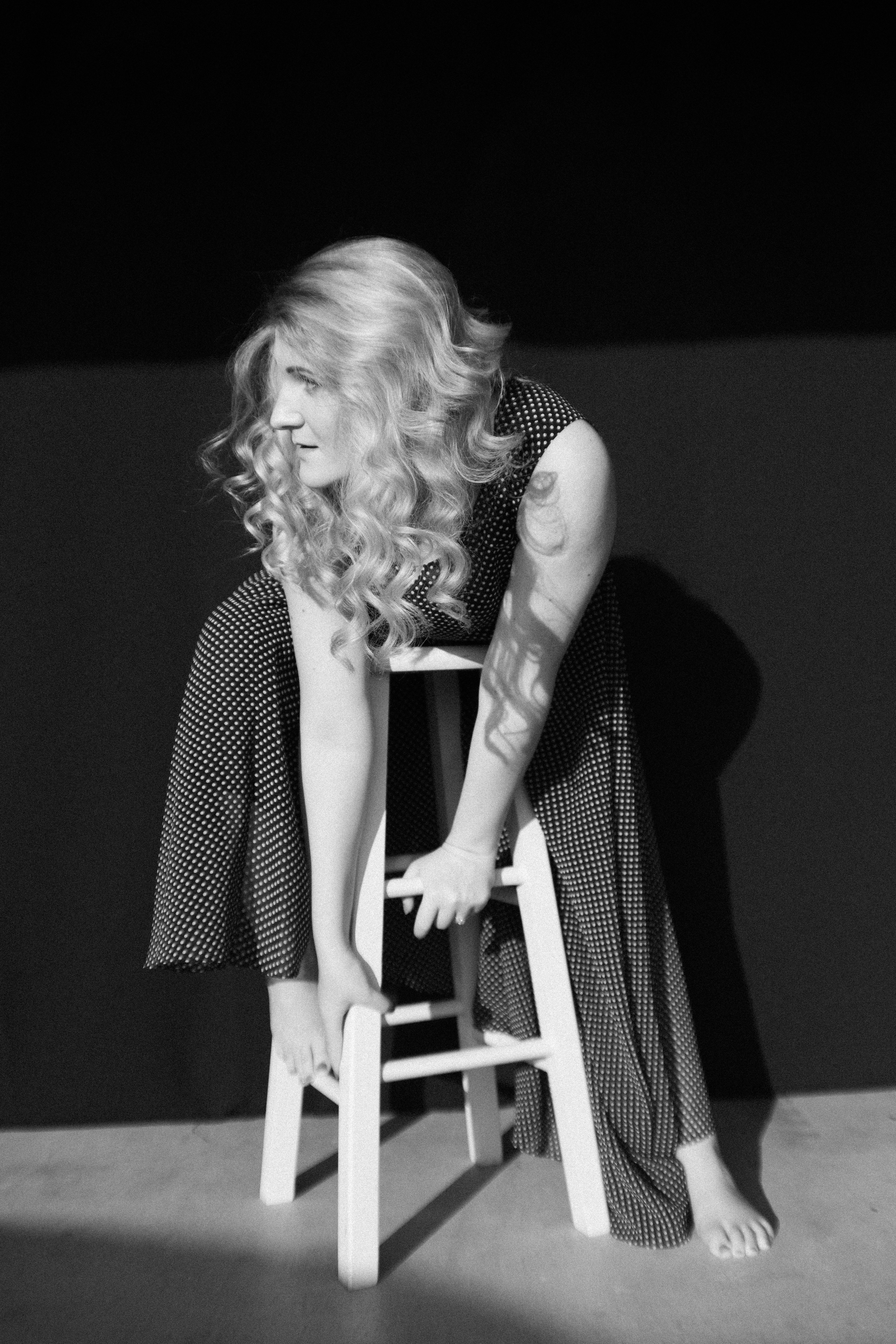 Noir Portrait: Curled Blonde Leaning Over a Stool