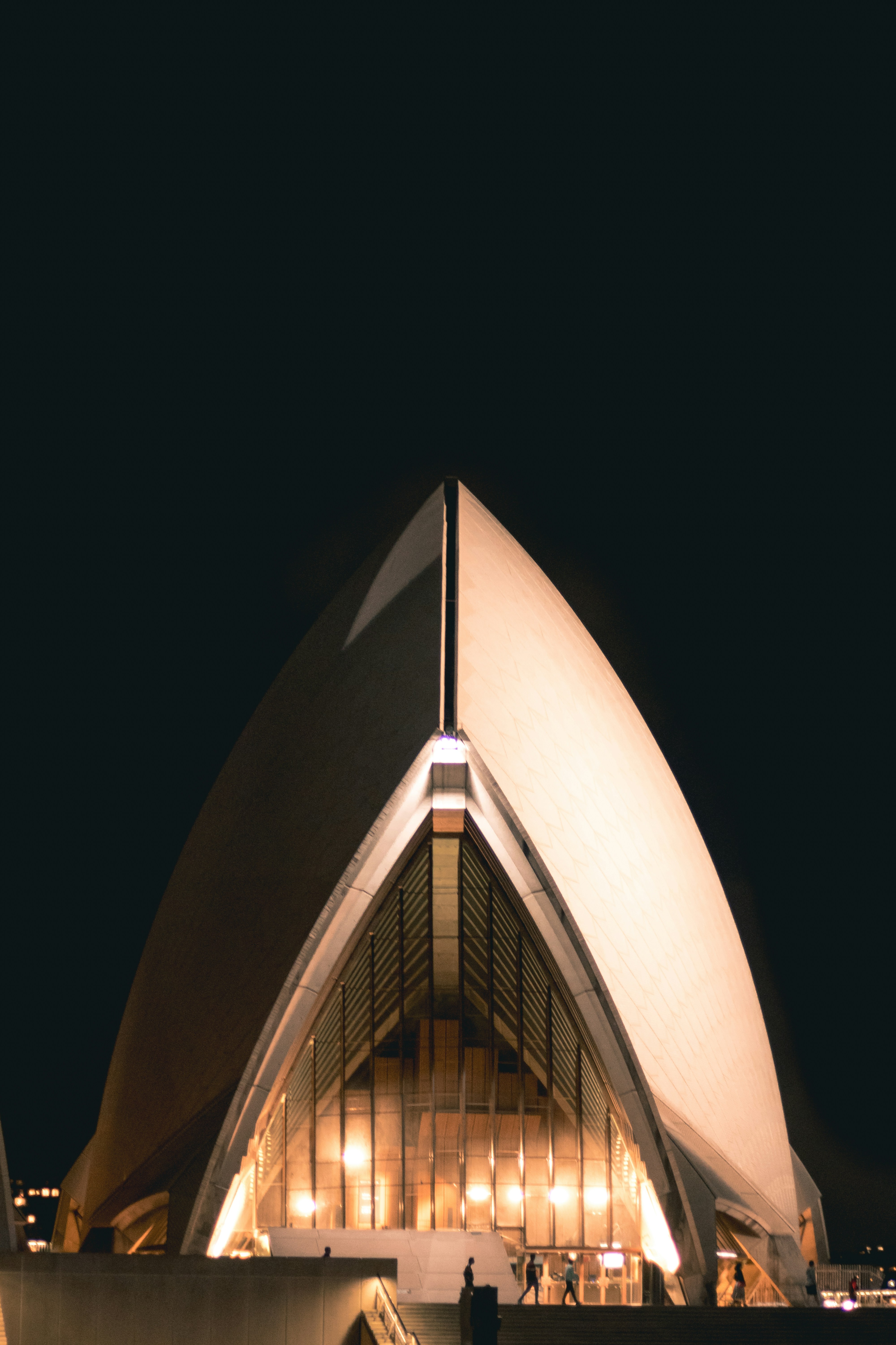 The iconic Sydney Opera House illuminated at night, showcasing its unique sail-like structure against a dark sky.