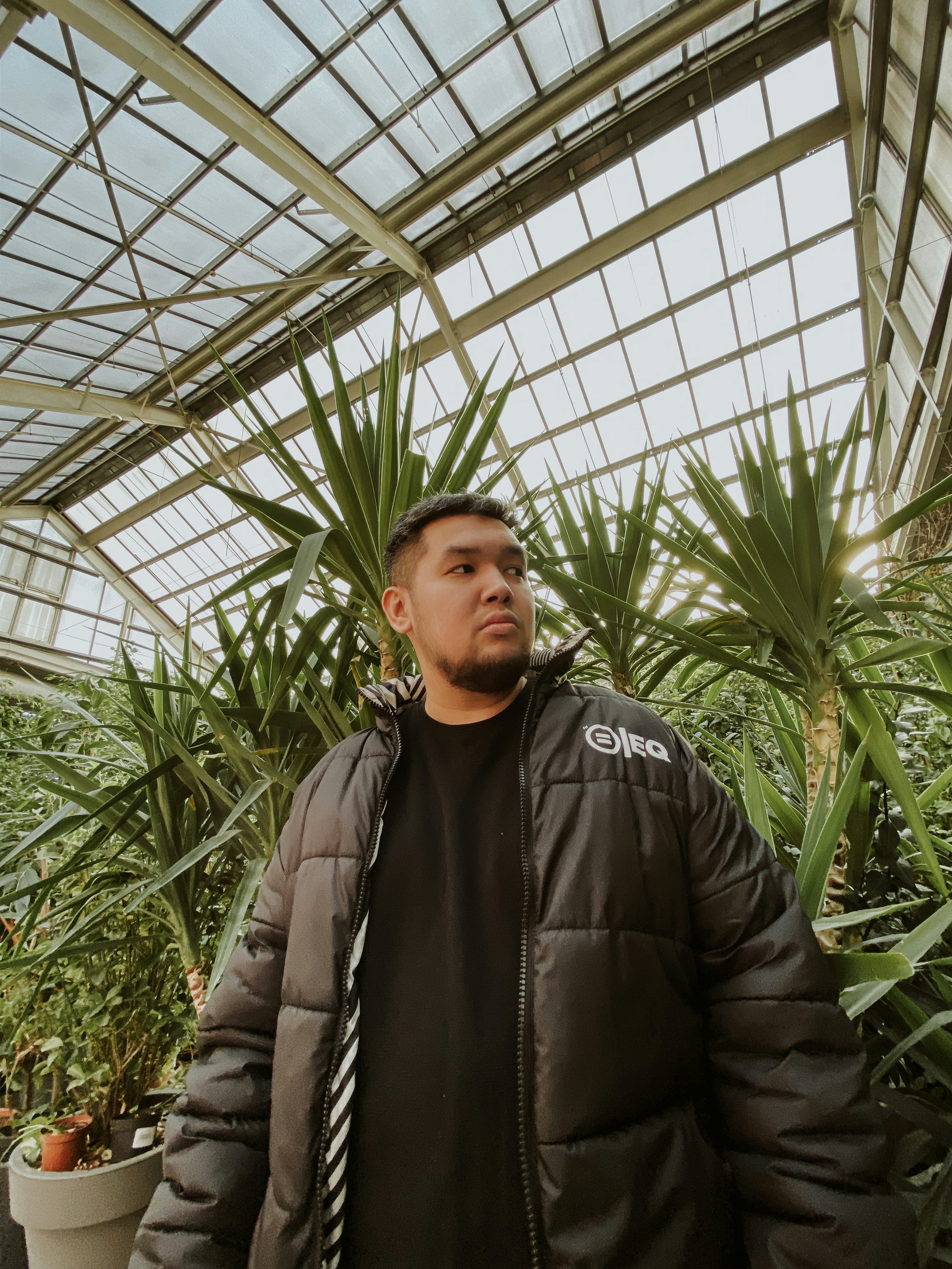 man in black leather jacket standing near green plants