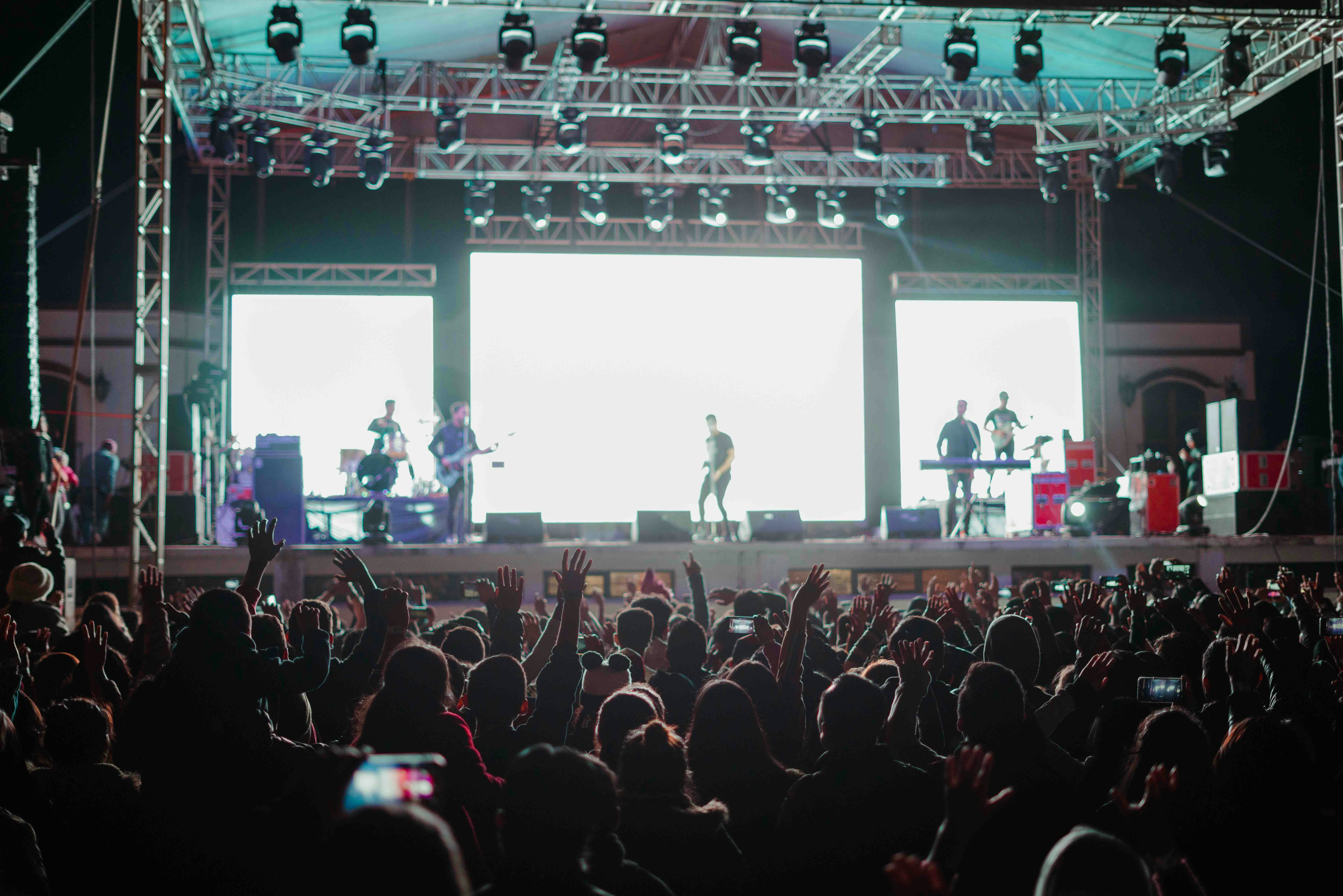 Crowd enjoying a vibrant live concert with bright stage lights against the night sky.