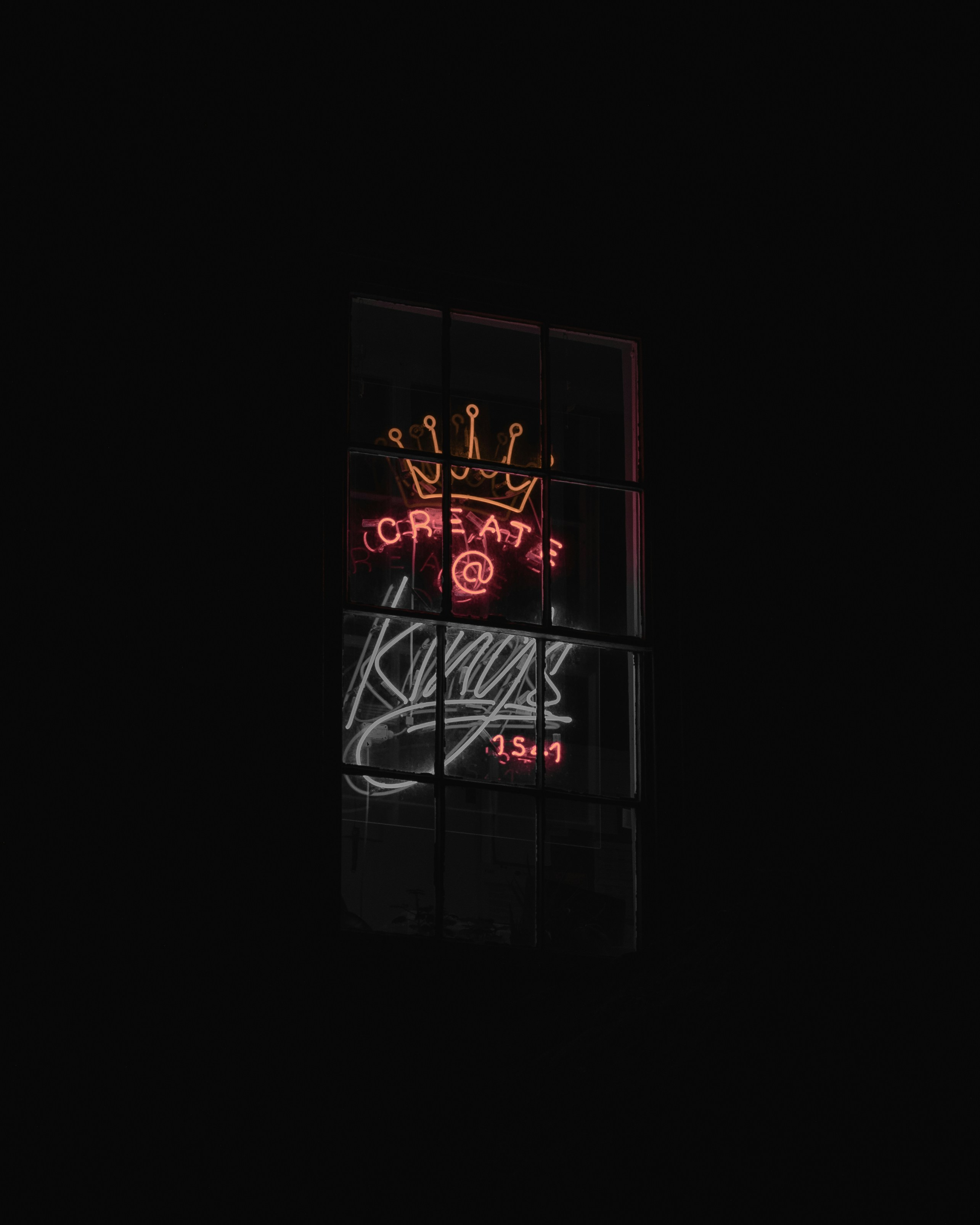 Neon sign displaying the word 'CREATE' framed by a window, glowing against a dark backdrop.