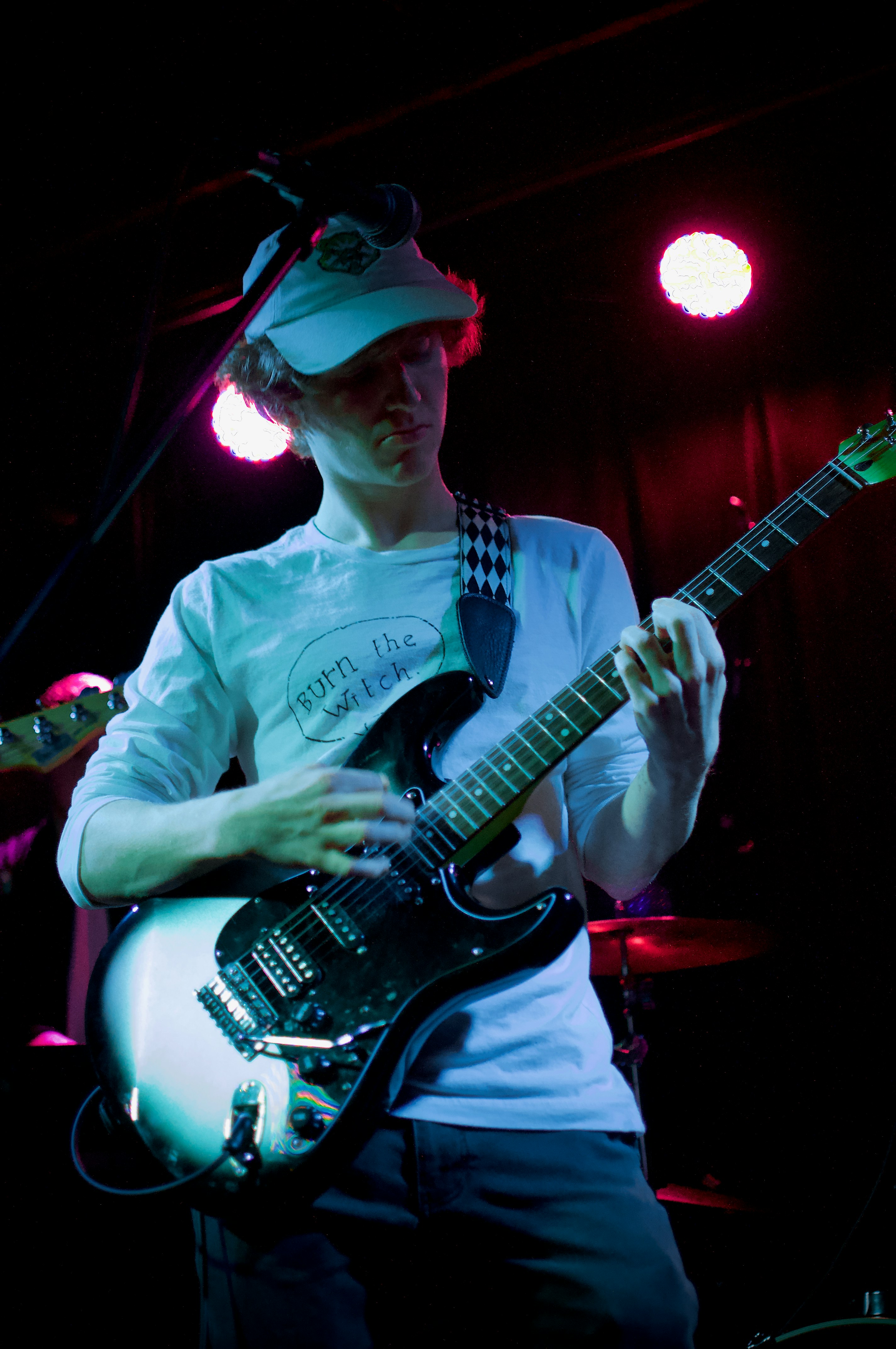 Musician passionately playing electric guitar on stage, illuminated by vibrant stage lights. The atmosphere captures the essence of live performance.