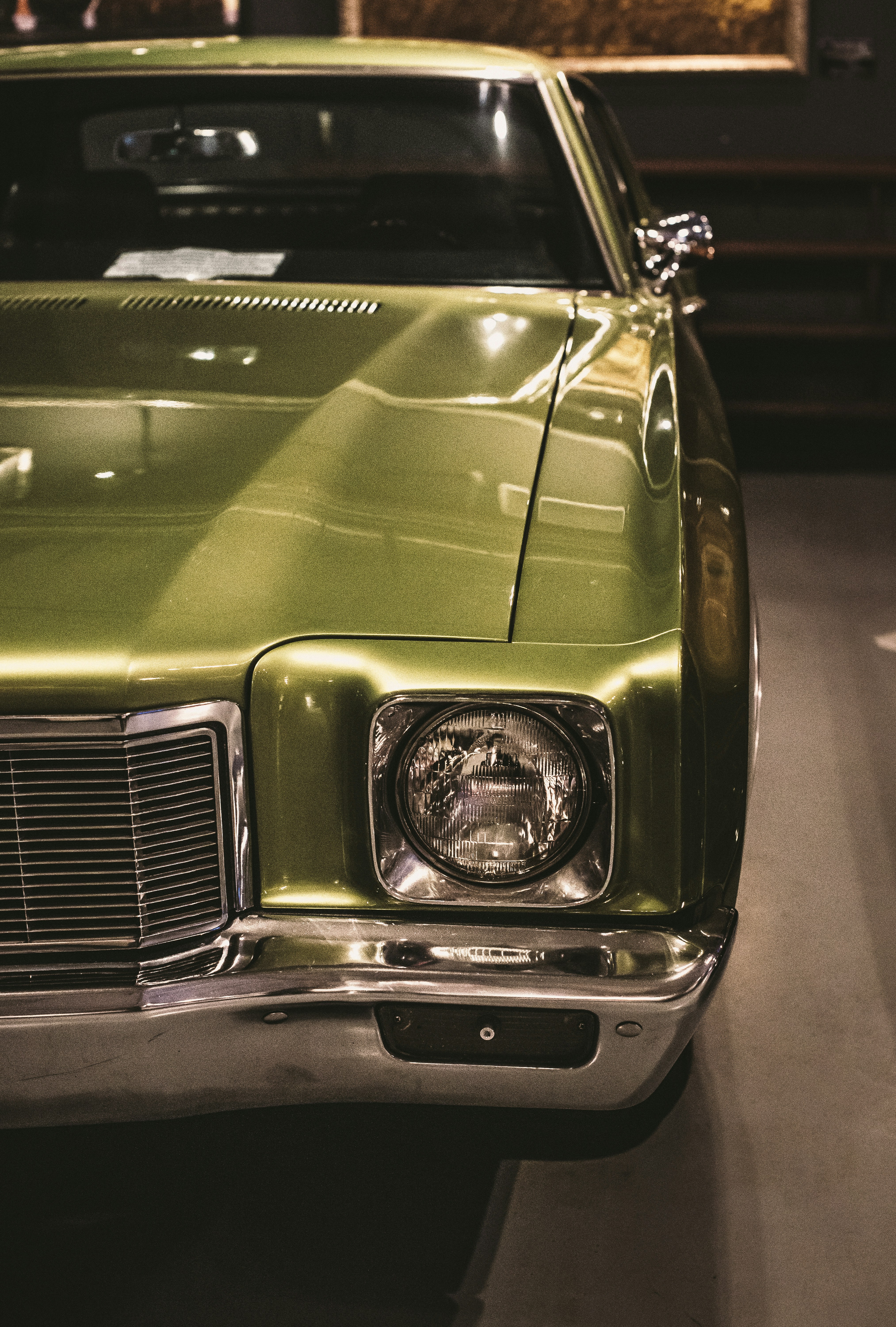Green Classic: A Chrome-Trimmed Headlight Glints in the Garage Light