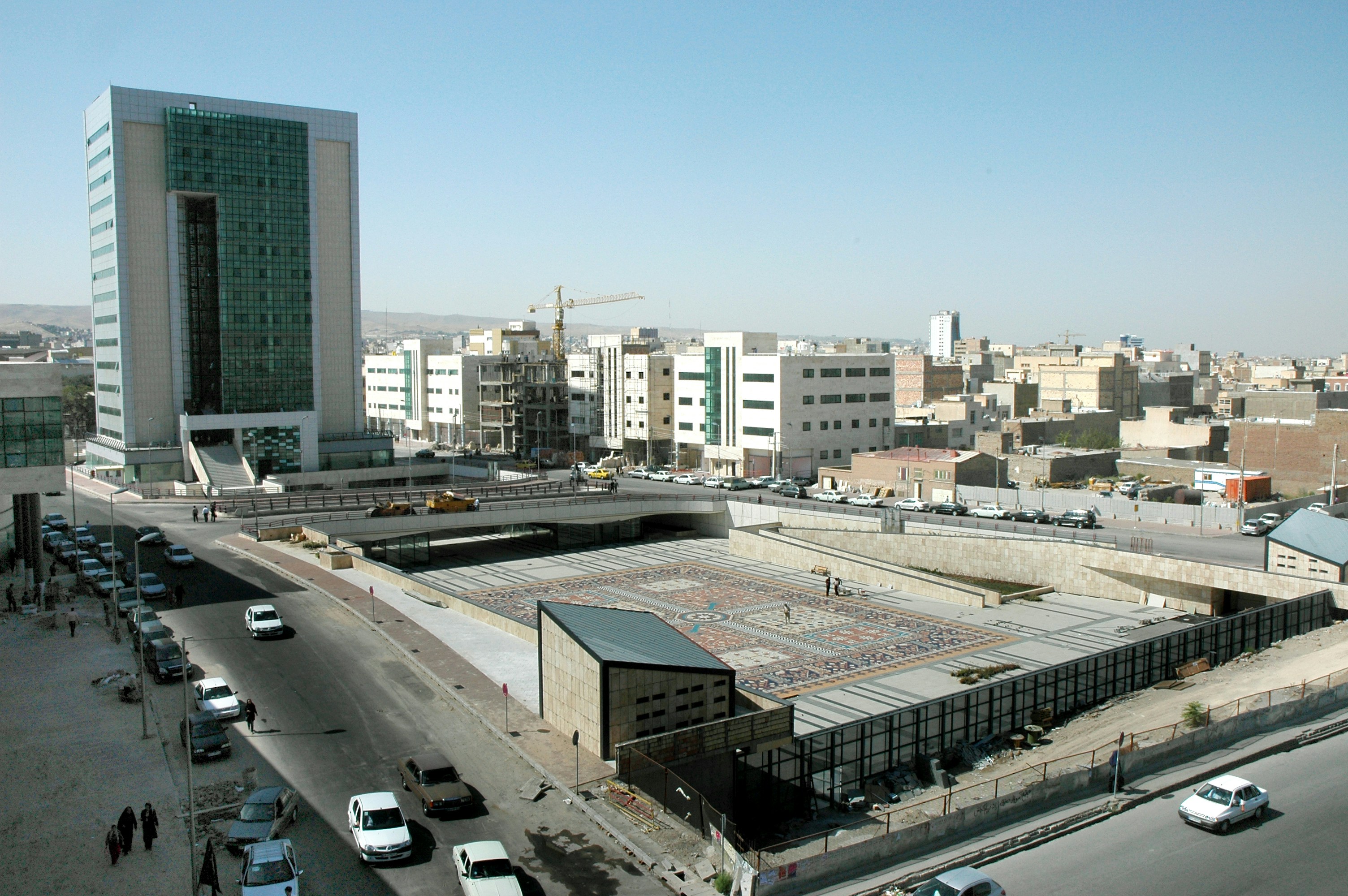 Cityscape featuring a construction site surrounded by modern buildings under a clear blue sky.