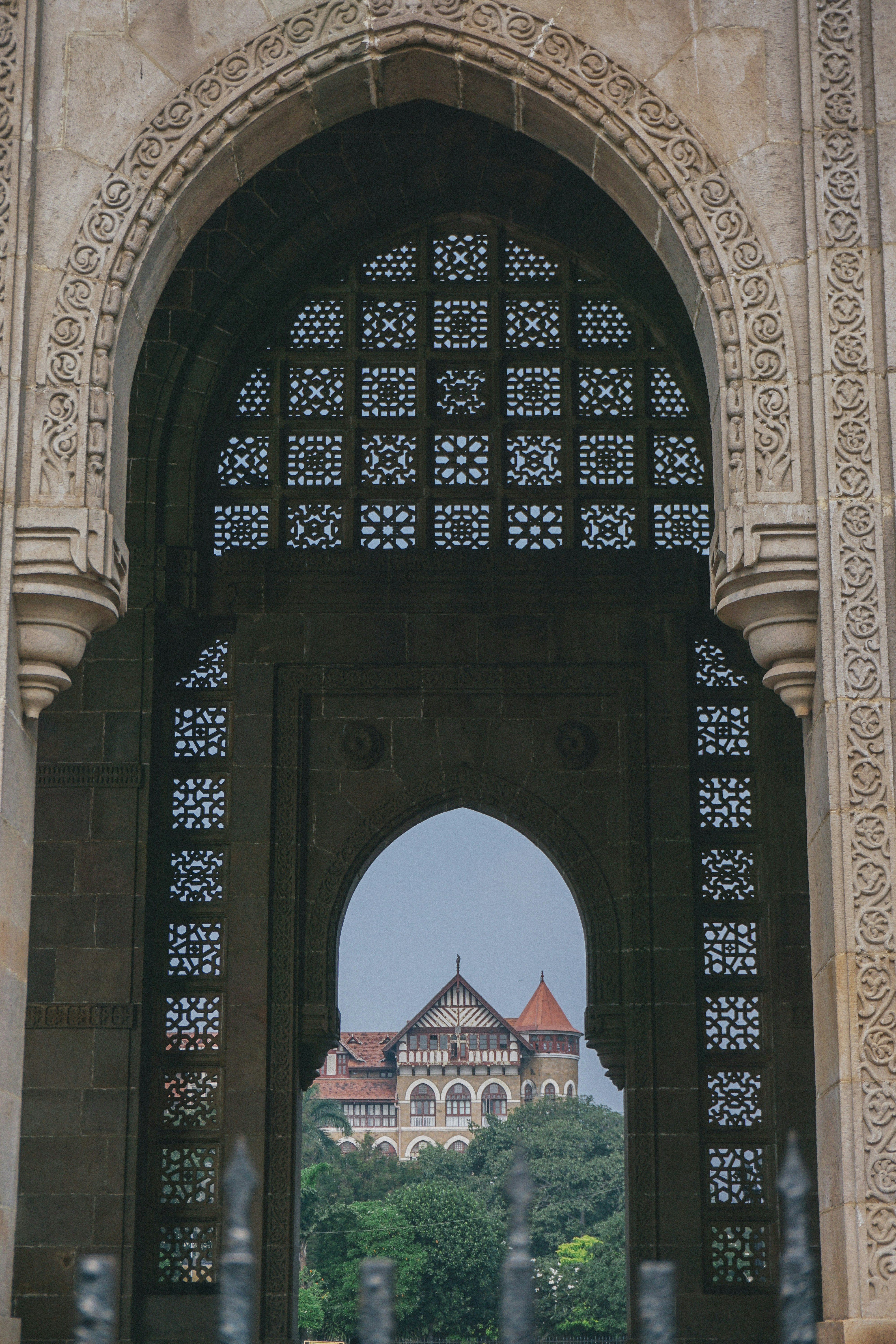 Intricate stone archway framing a historic building amidst lush greenery, showcasing architectural beauty.
