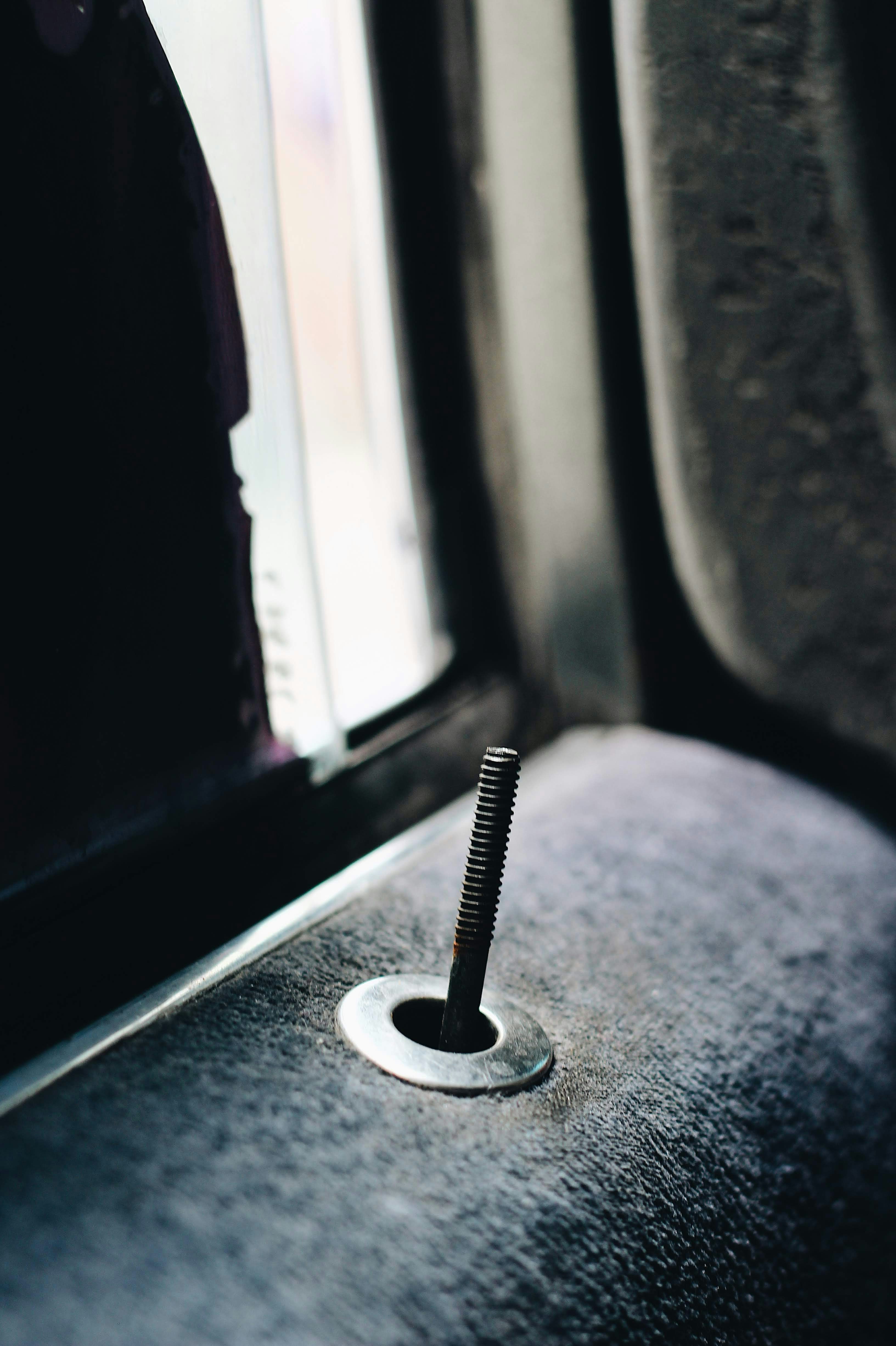 A Bolt of Quiet: A Single Stud Anchored in a Dusty Window Nook