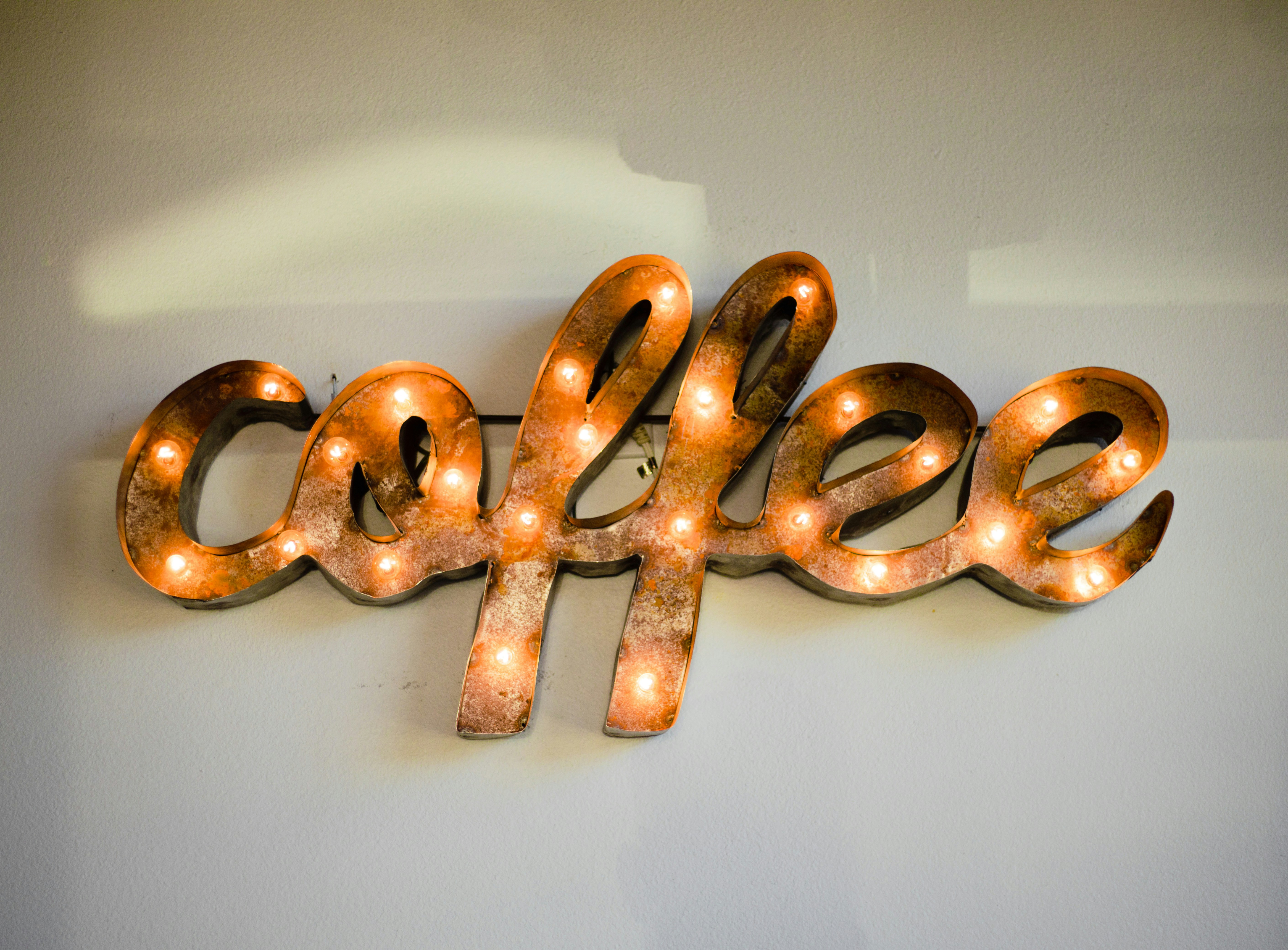 Amber Glow: The Copper Script Coffee Sign Illuminated by Vintage Bulbs