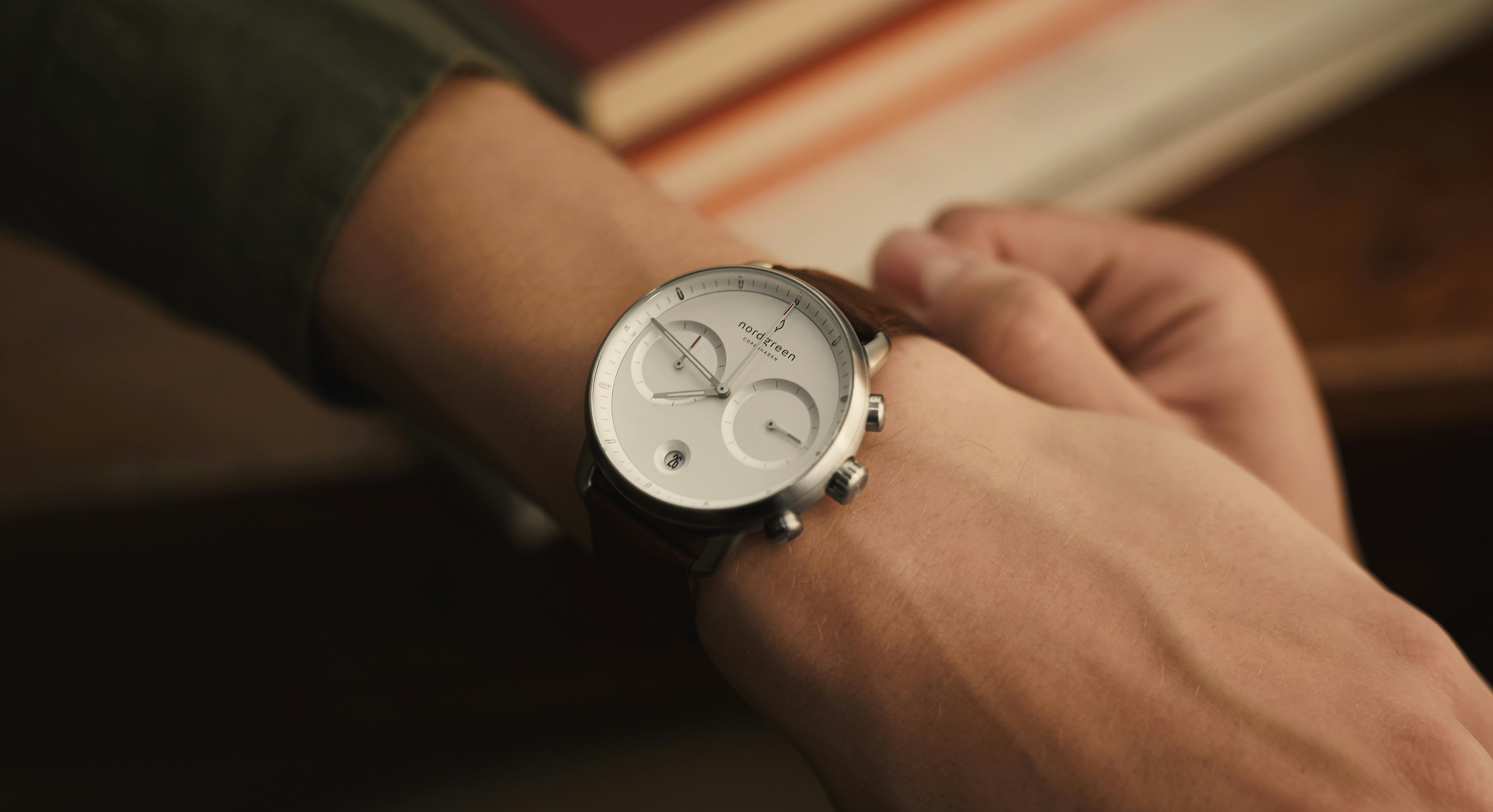 Close-up of a person wearing a silver round analog watch, showcasing minimalist design on a wrist.