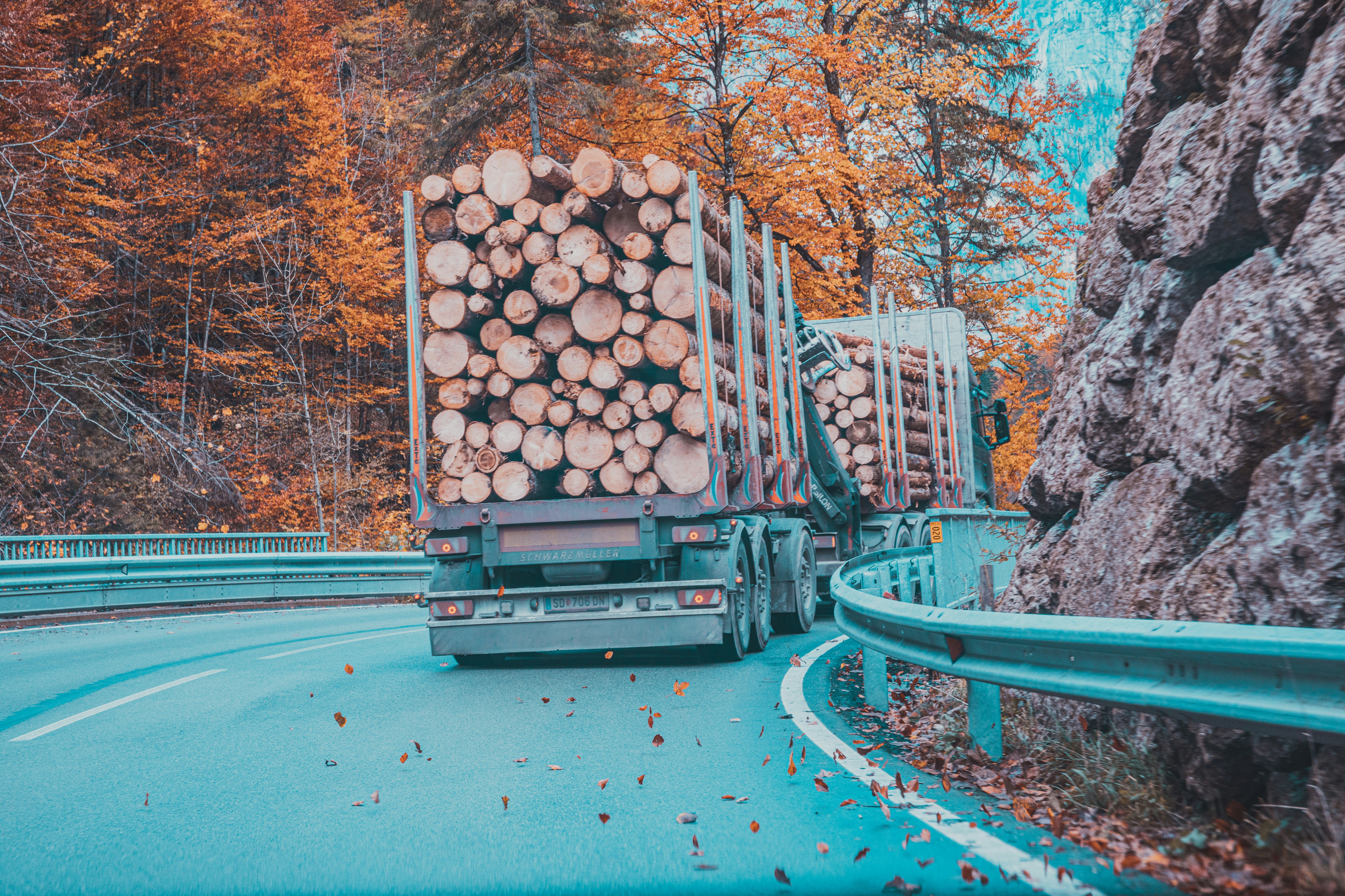 Log Carrier Rounds a Turquoise Bend on a Mountain Road