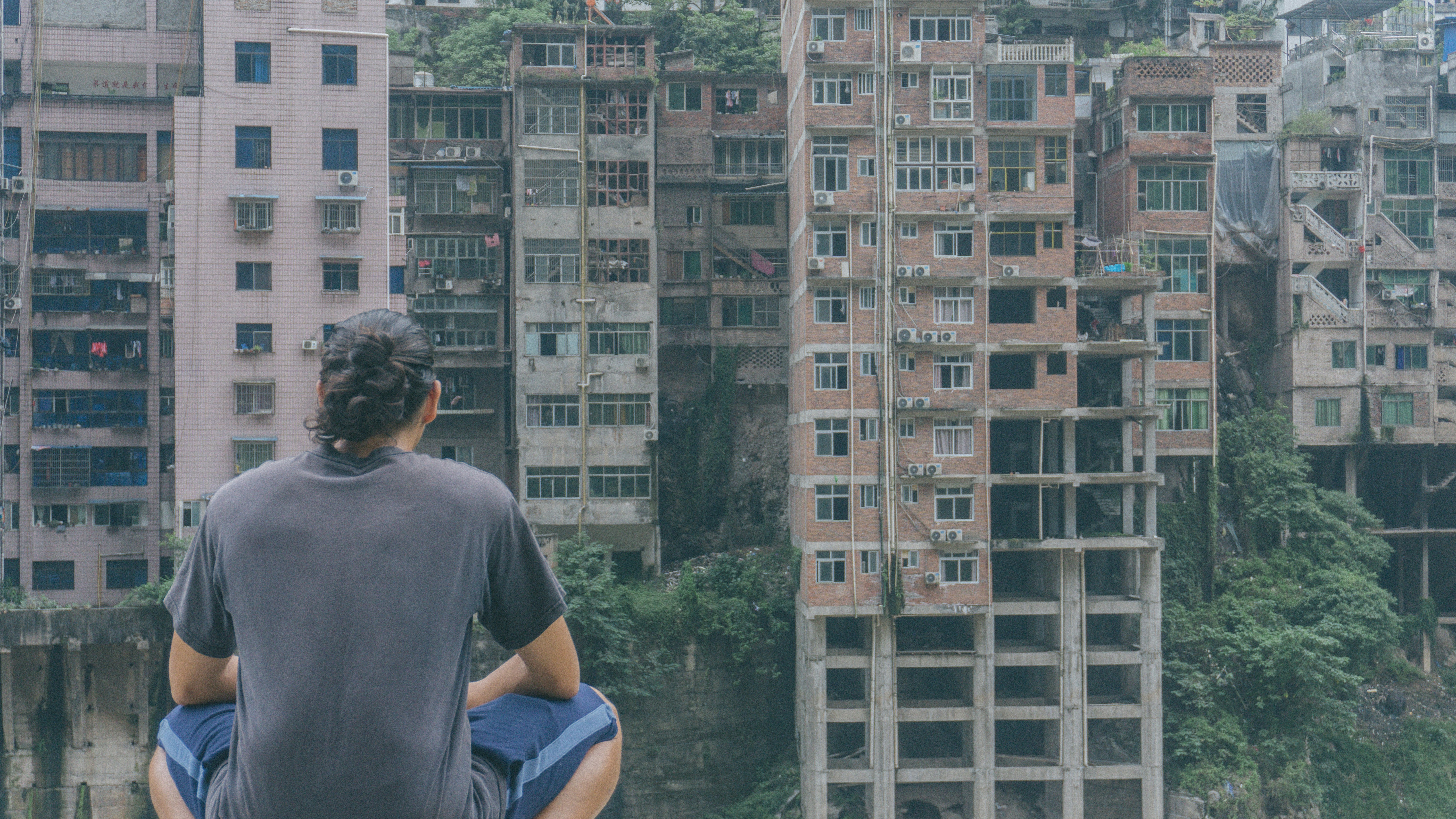 Rooftop Contemplation: A Silhouette Over a City of Concrete Windows