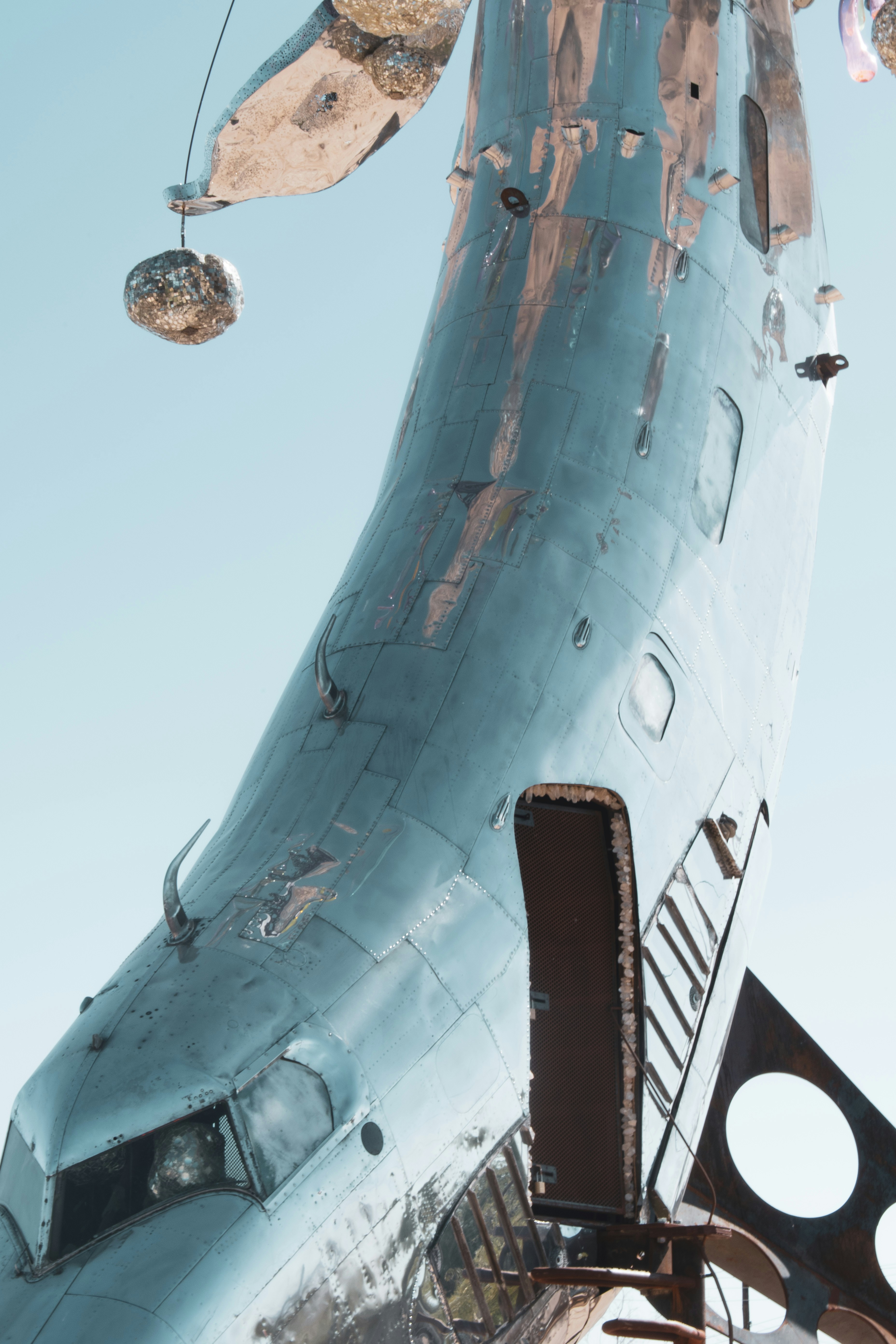 Cerulean Fuselage Lean: Open Hatch Amid Weathered Panels